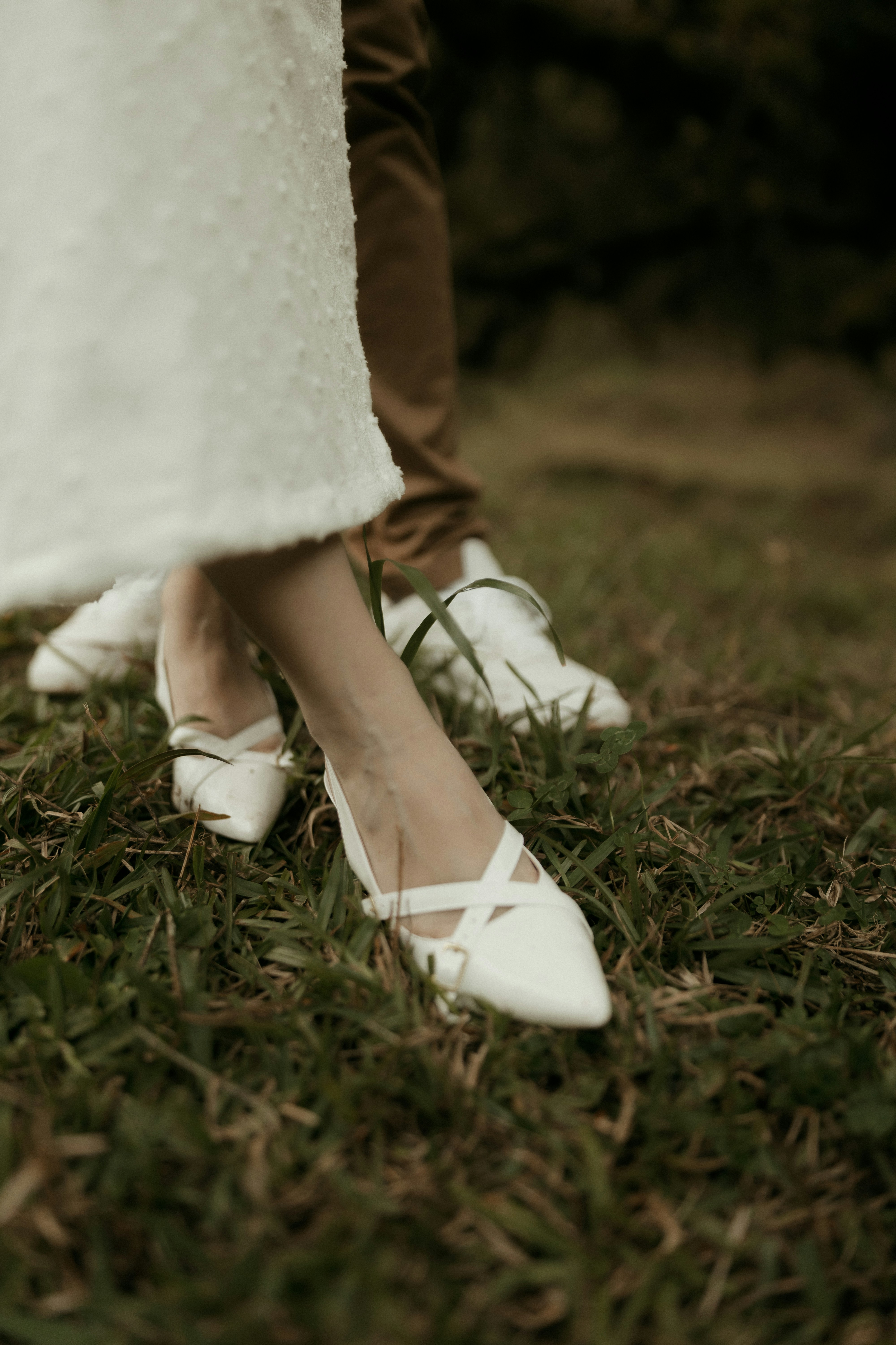 Bride and groom's shoes touch the grass in a soft, intimate moment