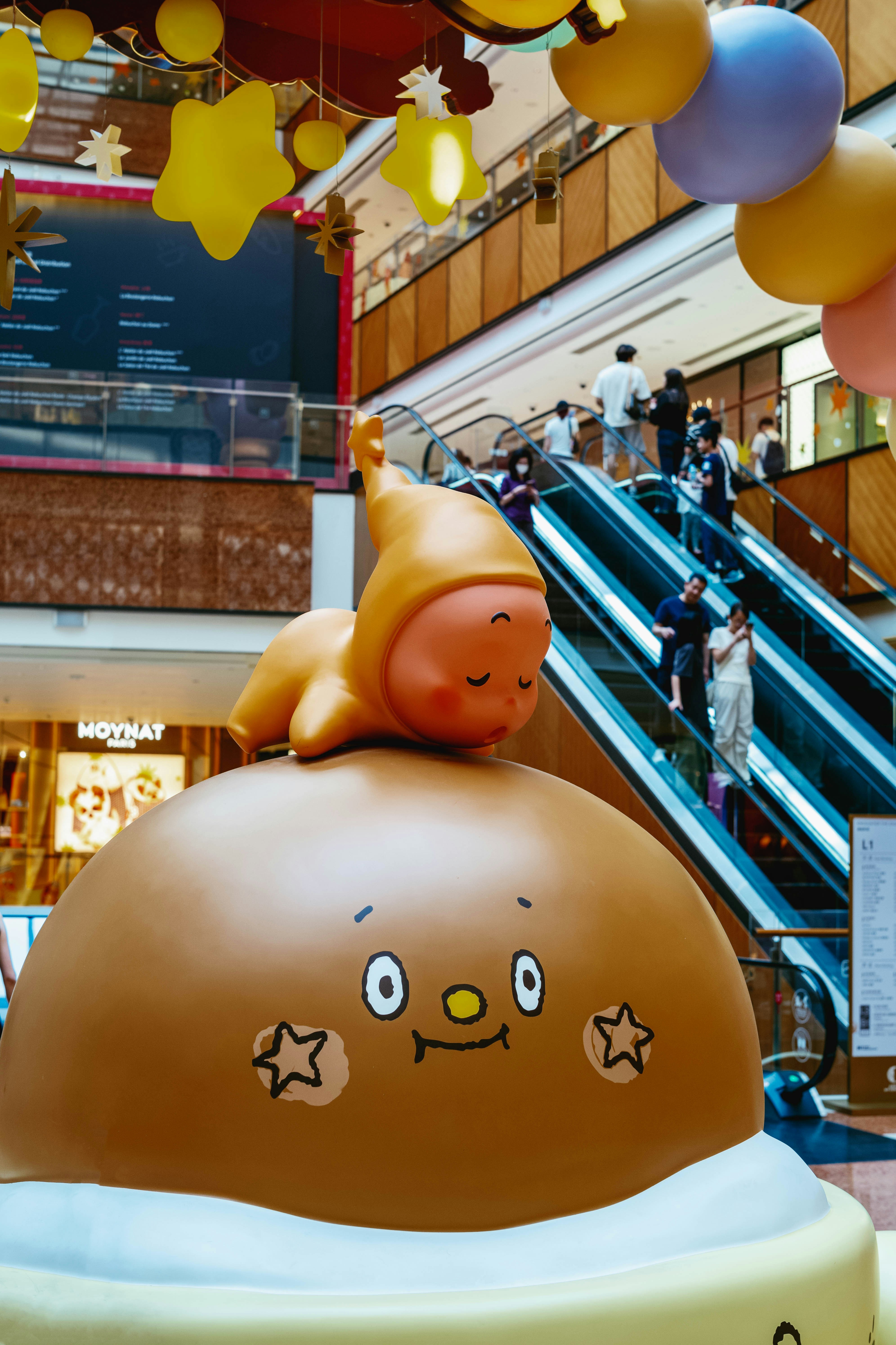 Gilded Balloon Toy in a Busy Shopping Atrium