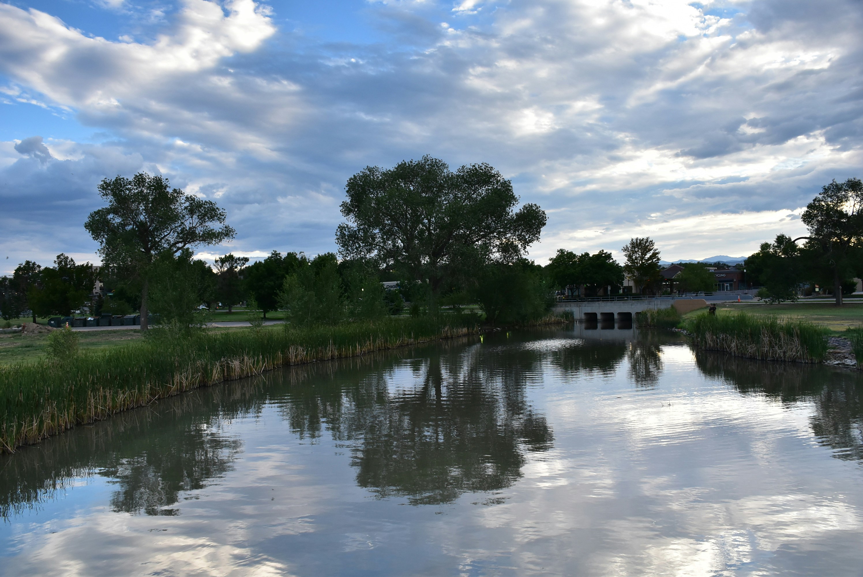 Serene riverscape reflected under a partly cloudy sky