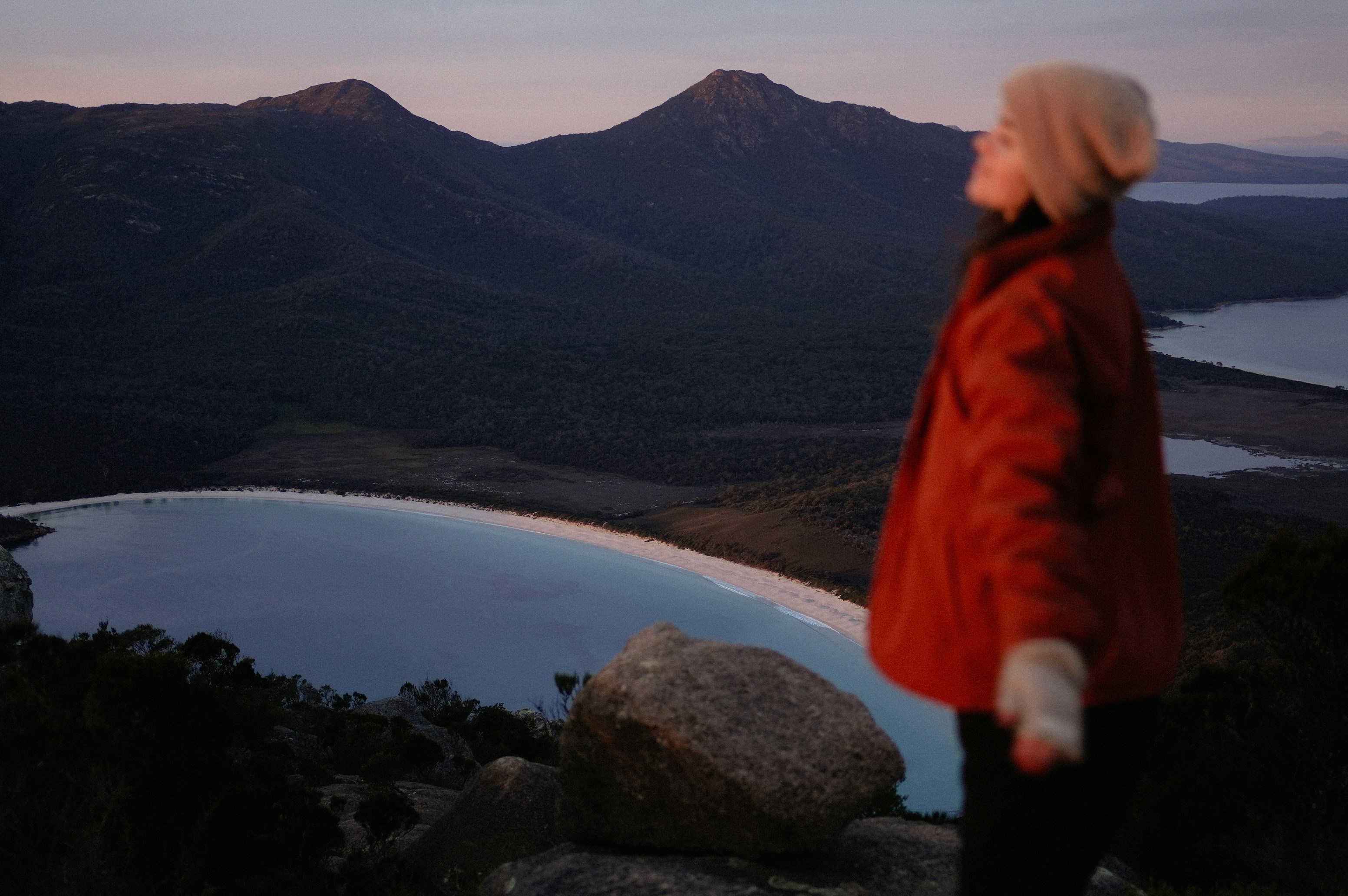 Red-clad silhouette at the rim: a quiet moment above the lake