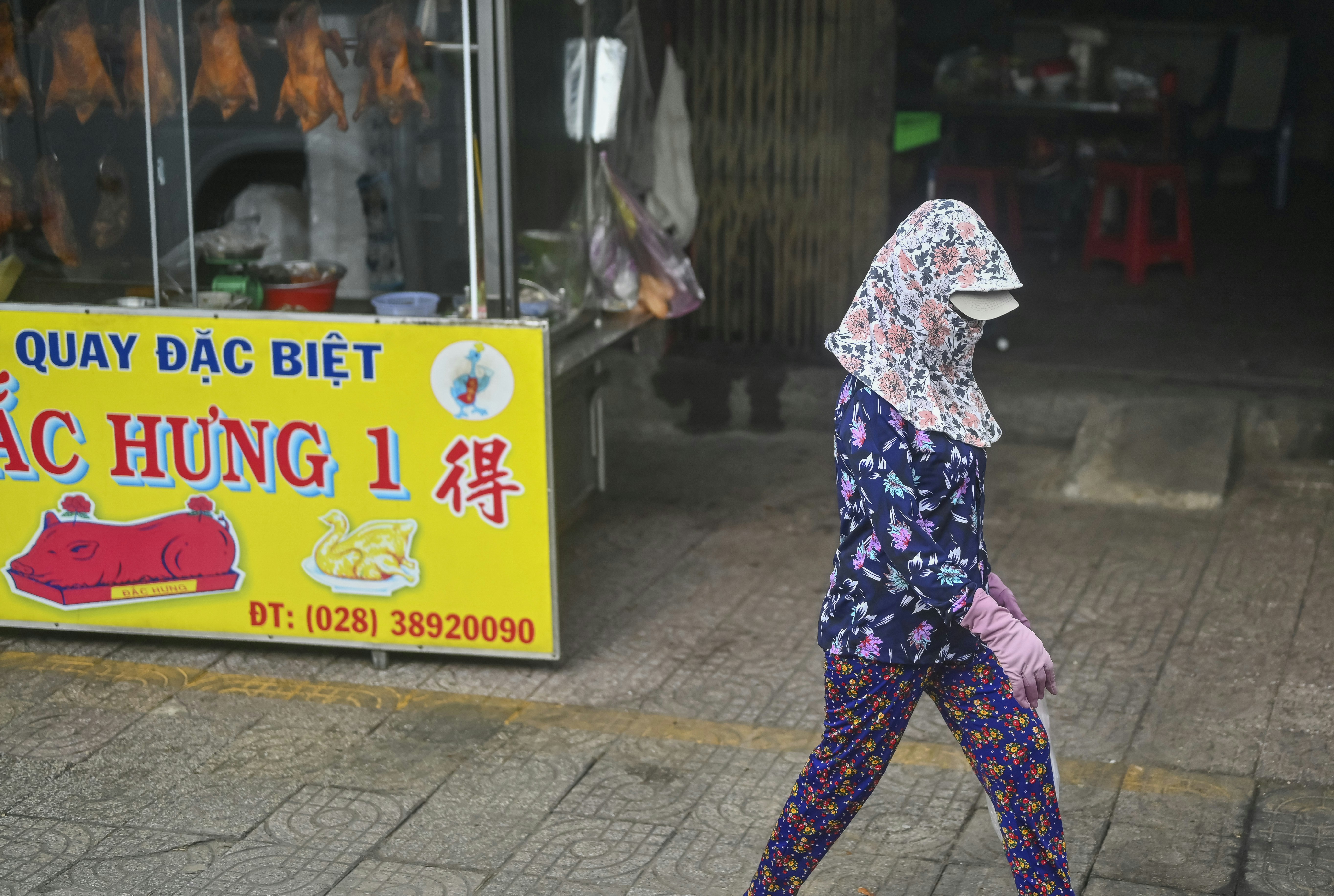 Masked pedestrian in floral leggings strides past a yellow storefront sign