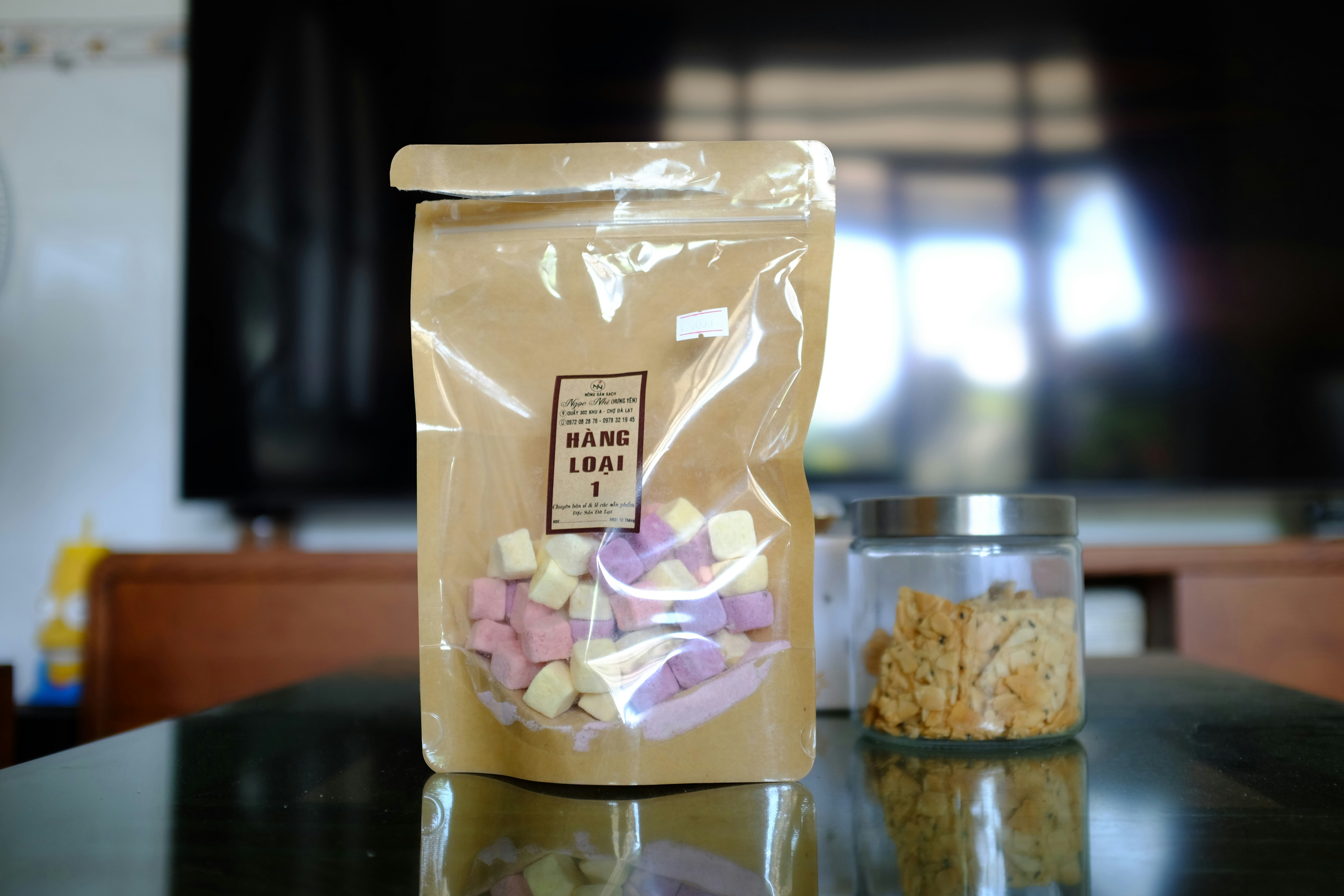Snack sachet on a reflective kitchen counter with a glass jar in the background