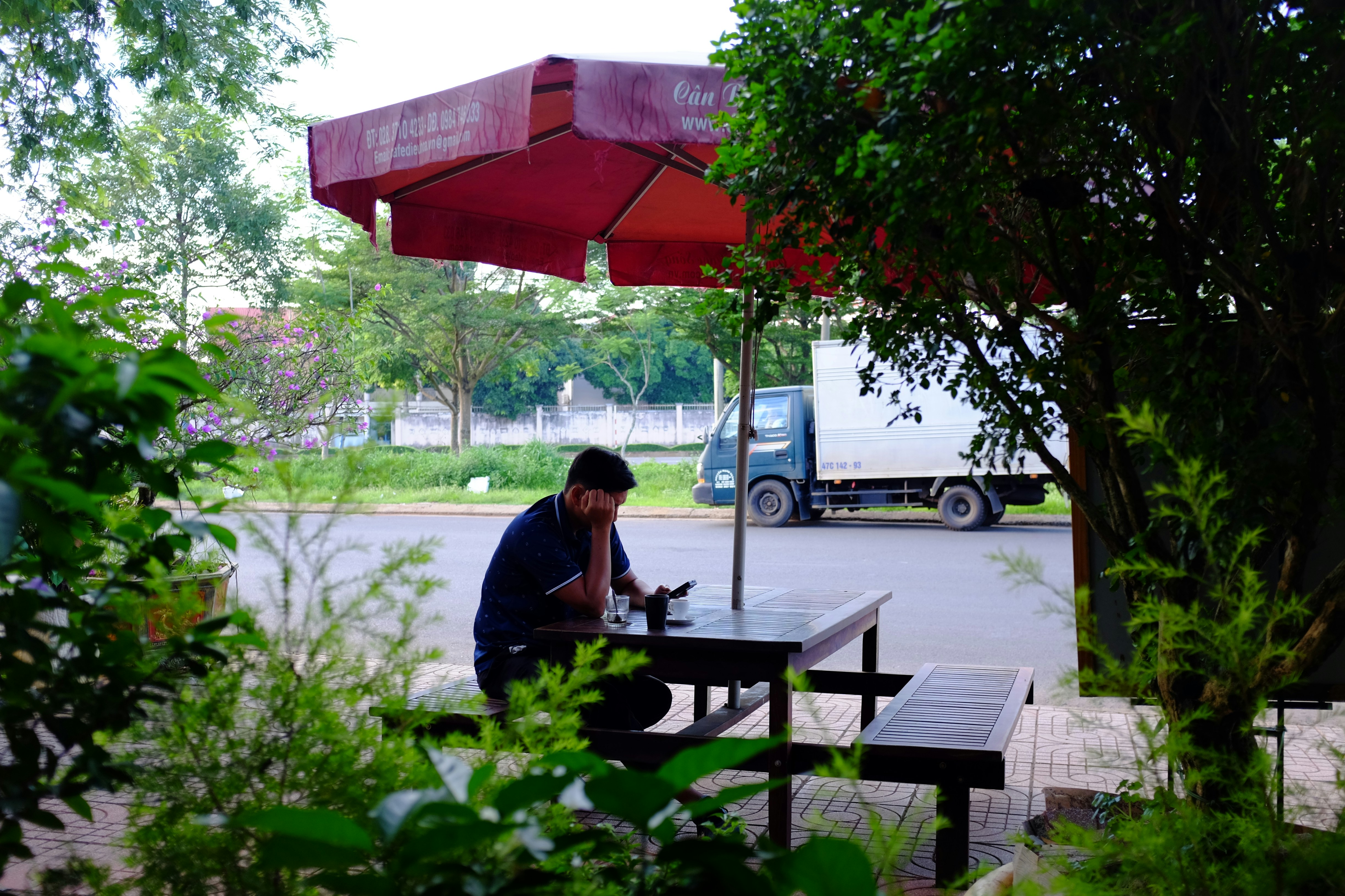 Solitary Table Under Red Canopy: Quiet Pause by the Park