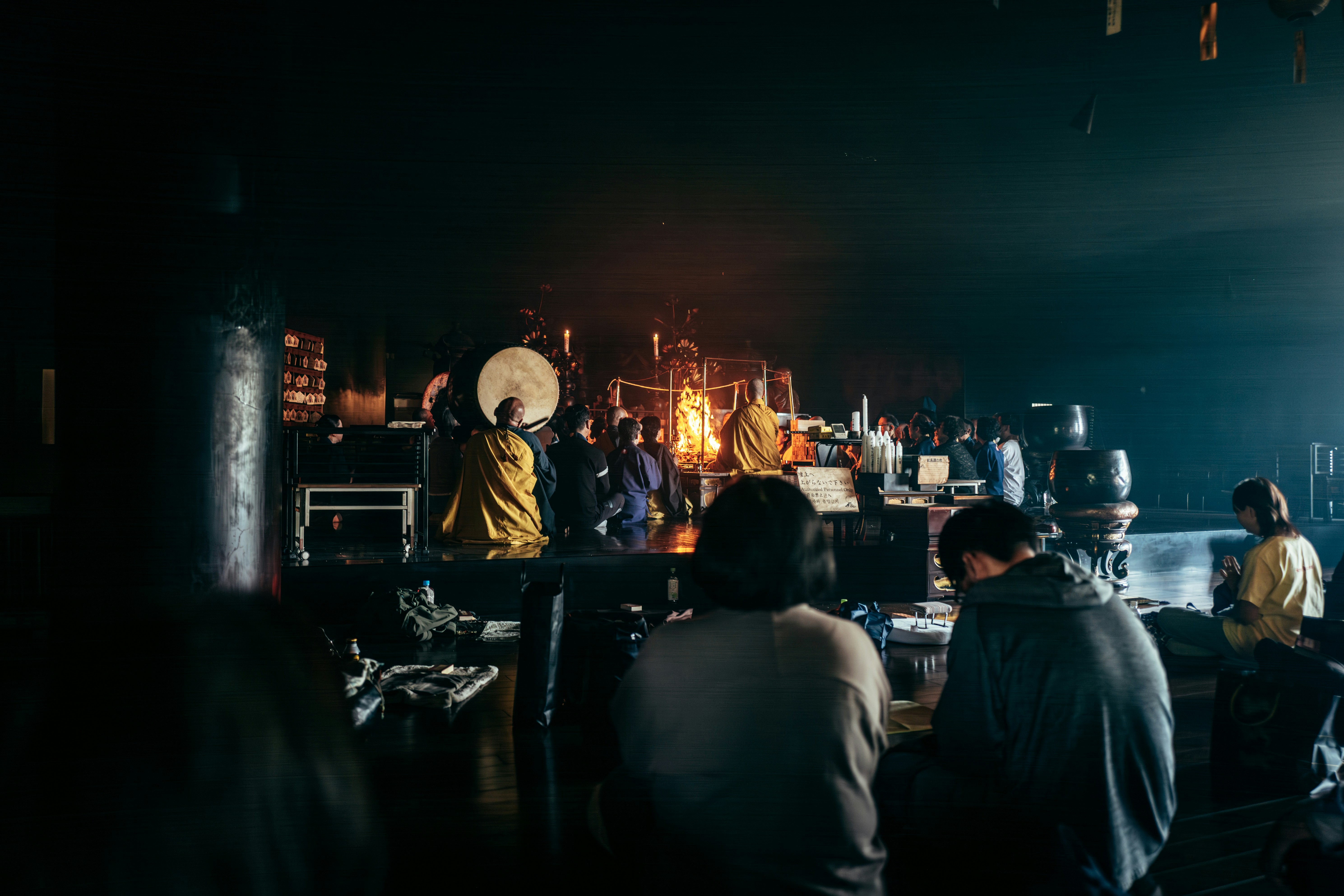 Buddhist monks performing a sacred fire ritual (Goma) inside a dimly lit temple, creating a powerful, spiritual and mystical atmosphere.