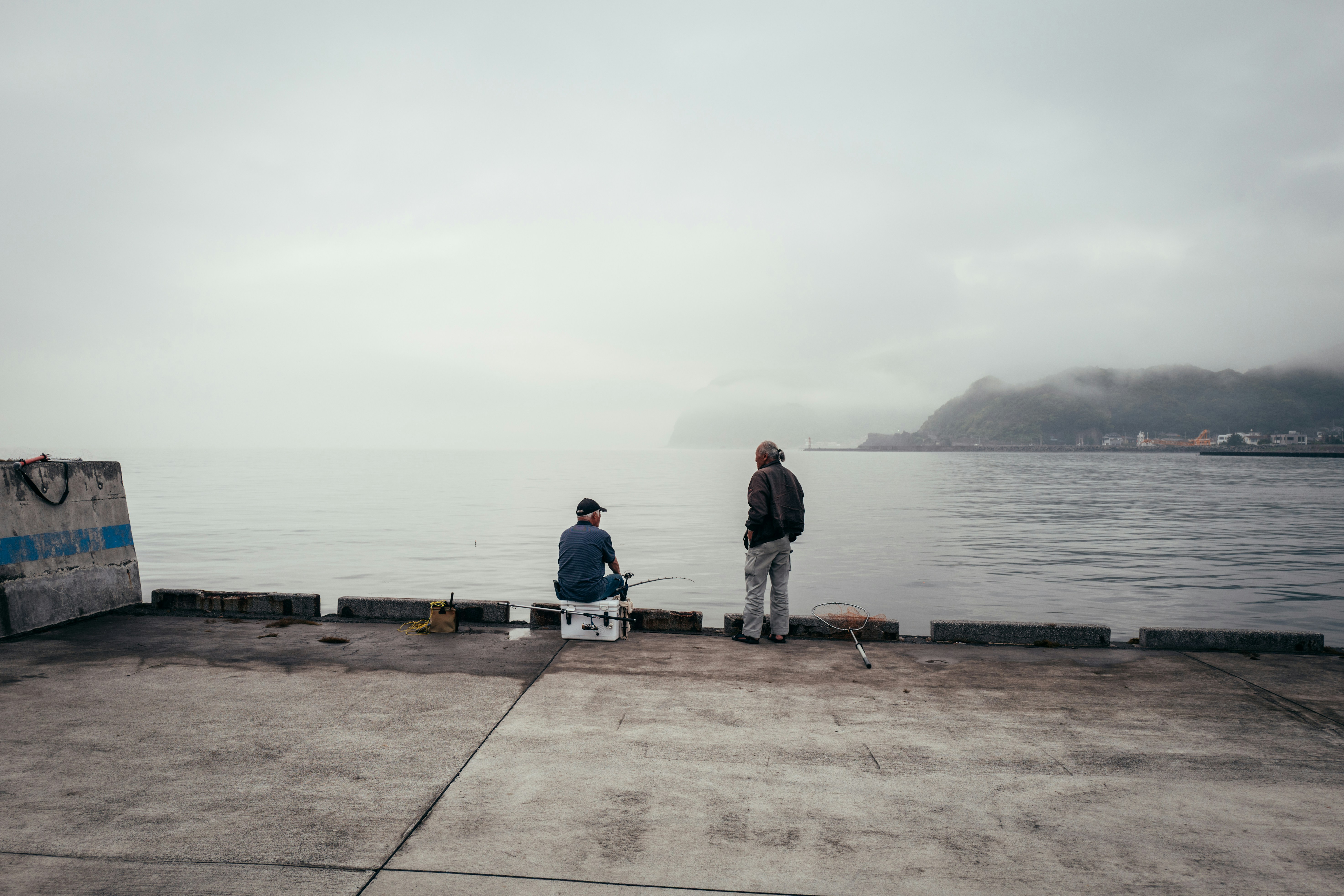 Two Anglers at a Quiet Pier Under Misty Horizon