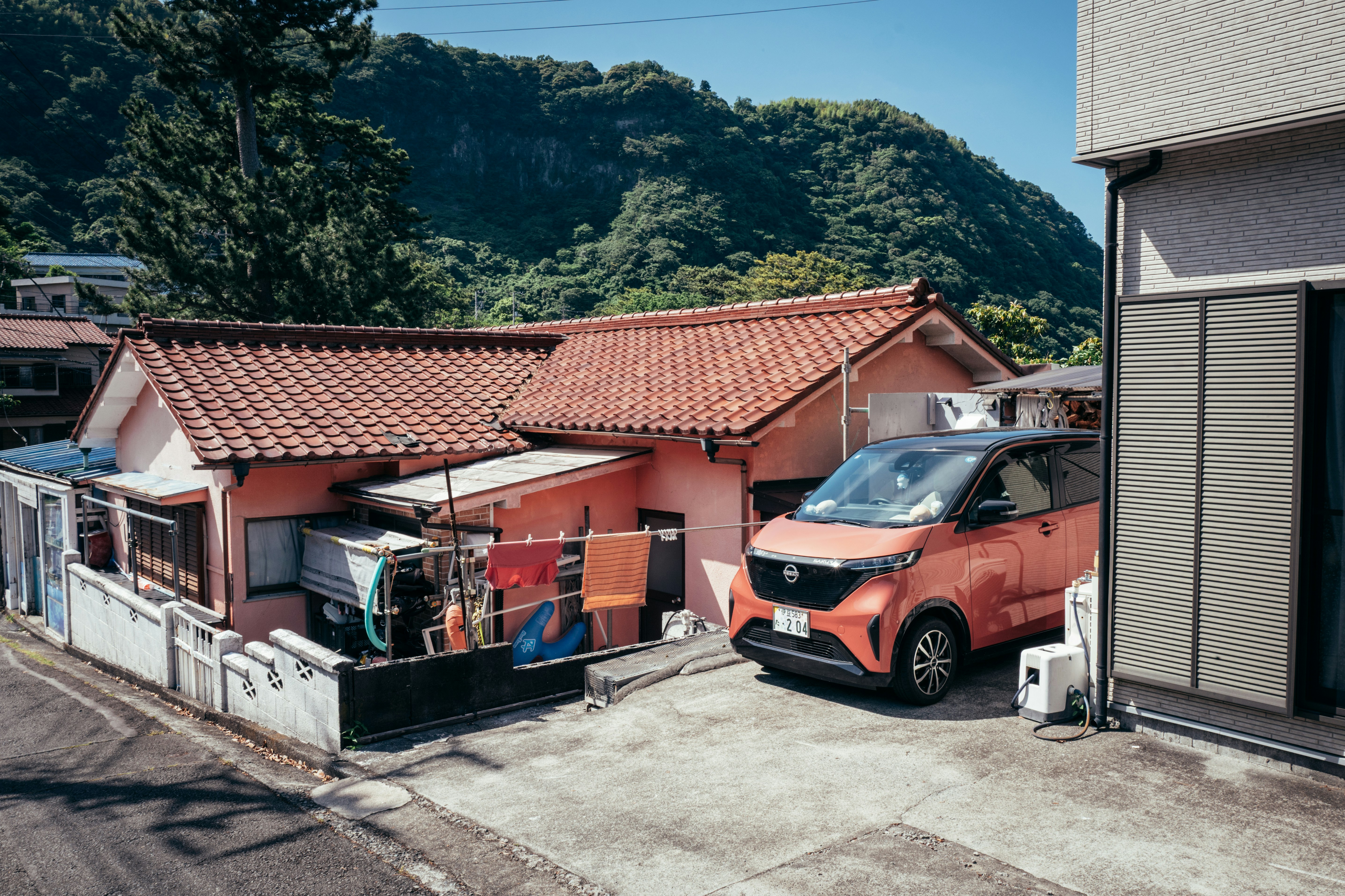 Orange van in a sunlit Japanese alley between houses