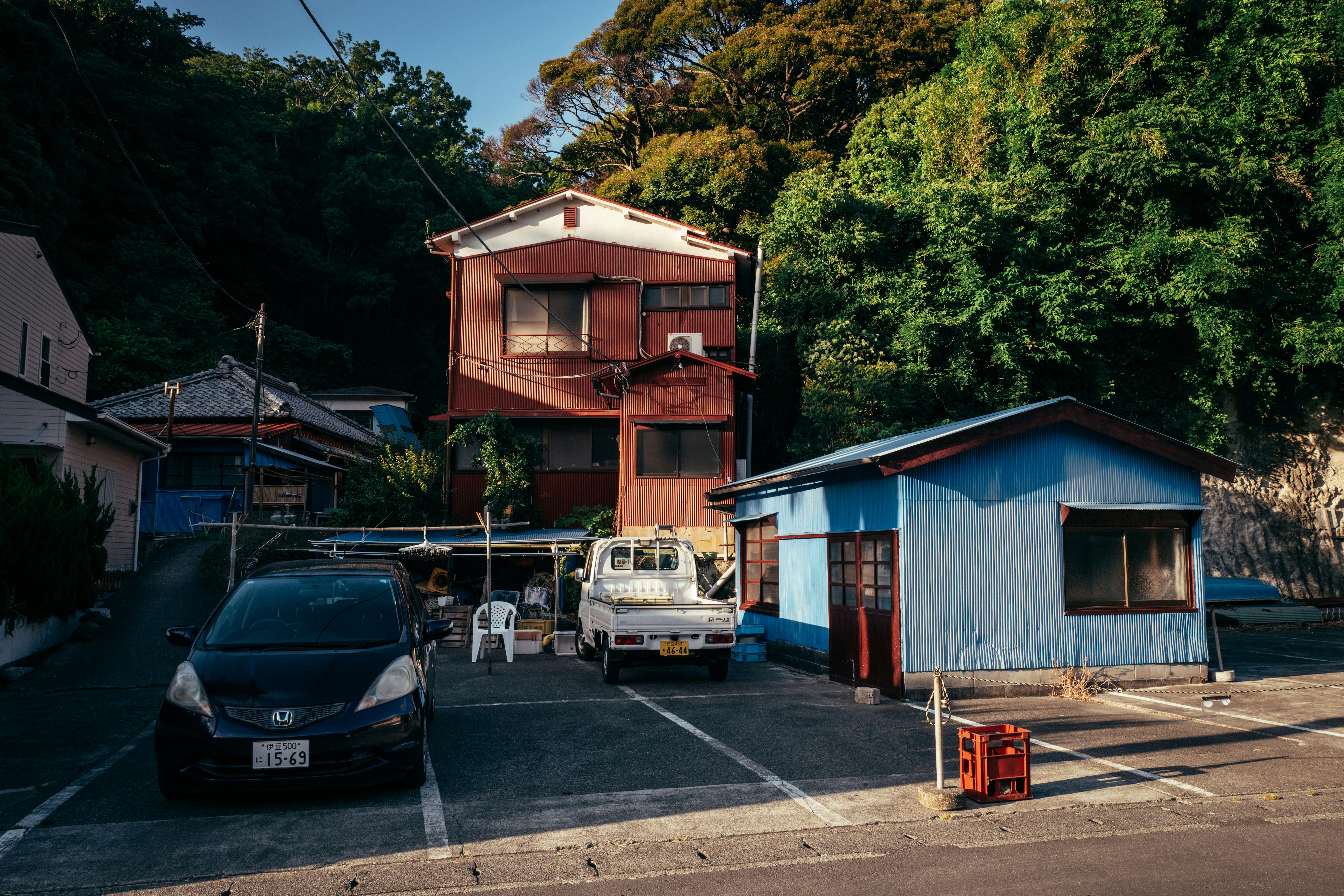 Quiet Streetfront: A Two-Story Orange Building Framed by Trees and Trucks