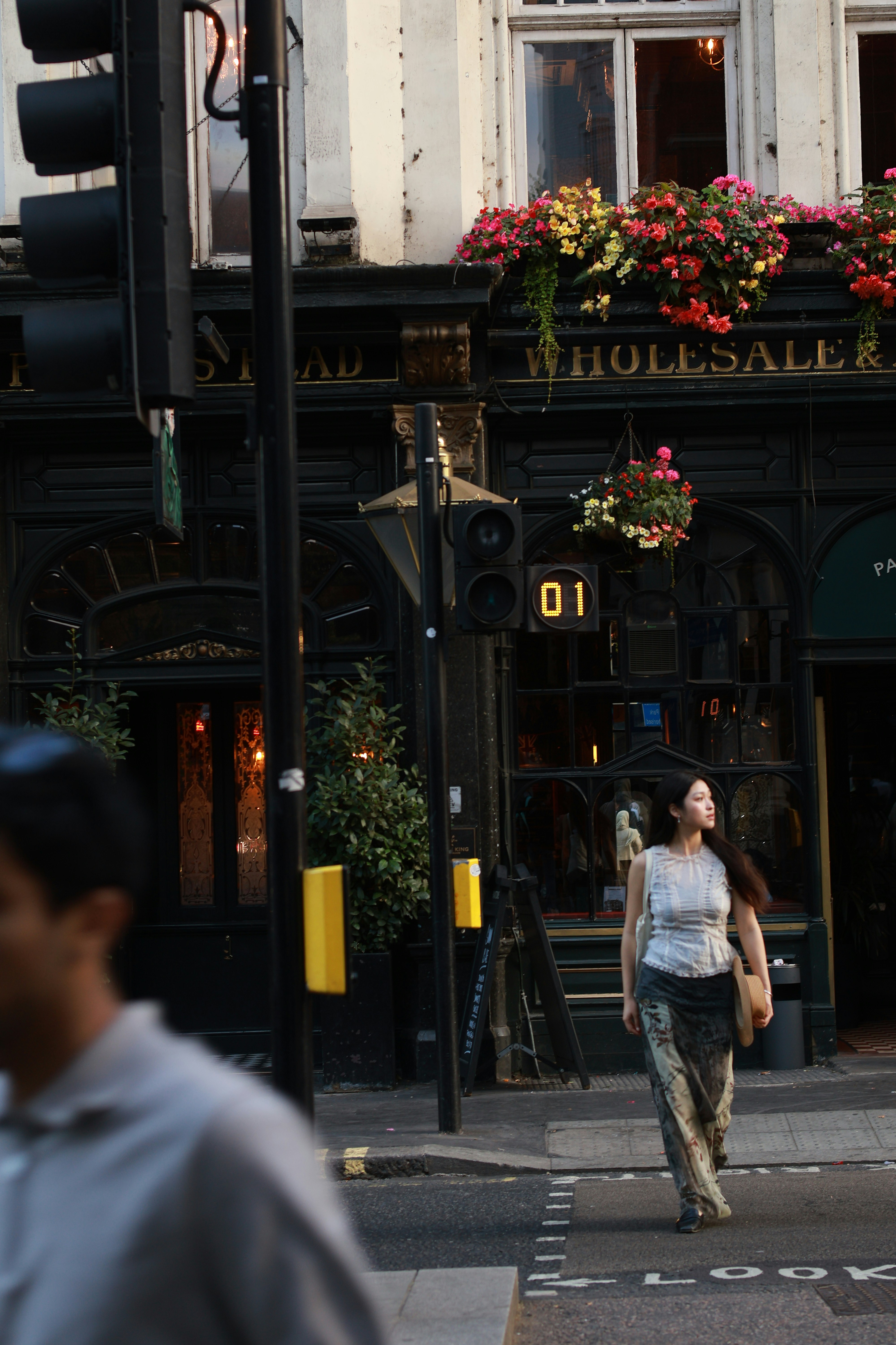 City pedestrian near a vintage storefront with hanging flower baskets