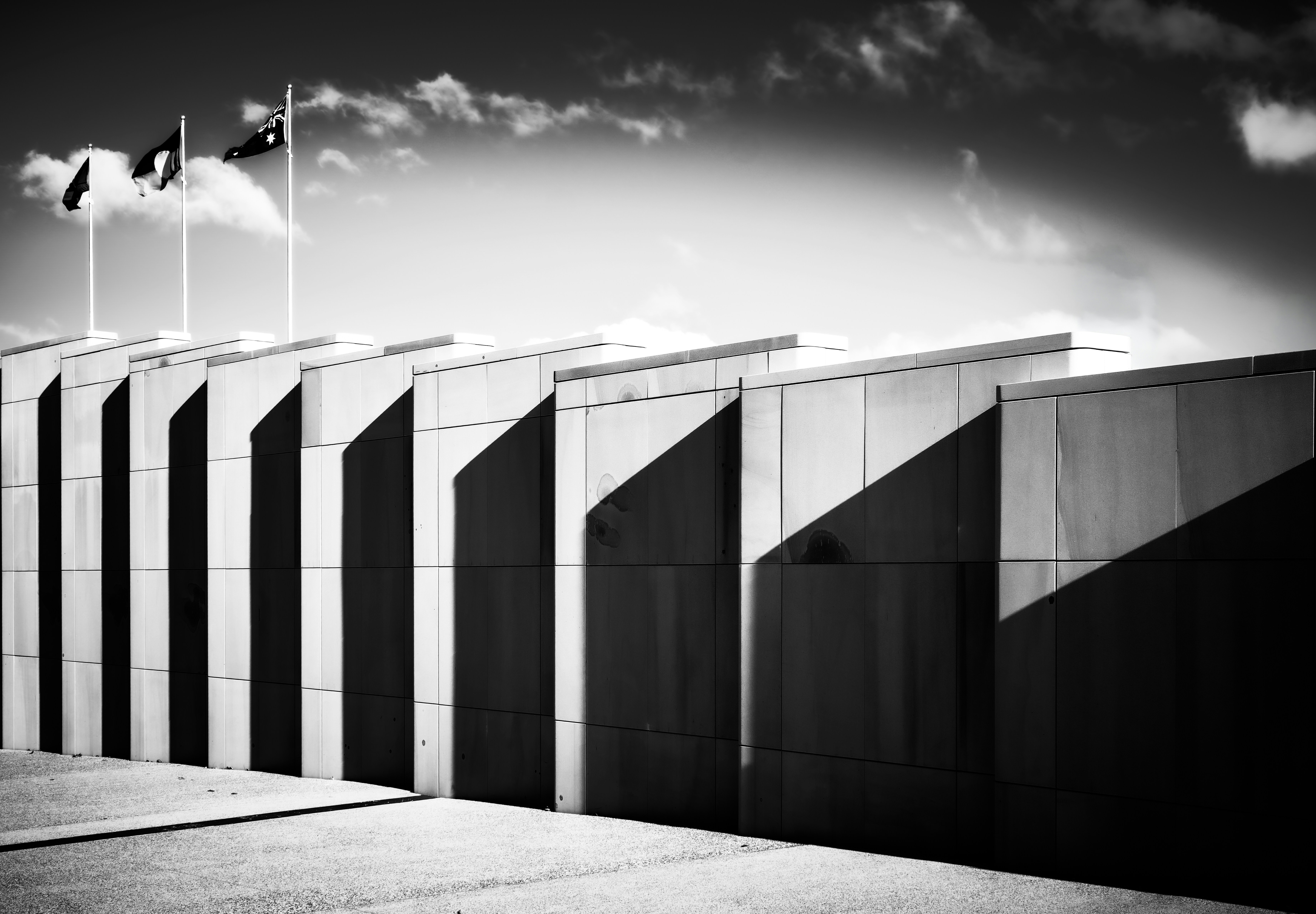 Shadows and Facades: A Row of Angled Monoliths Under a Narrow Sky