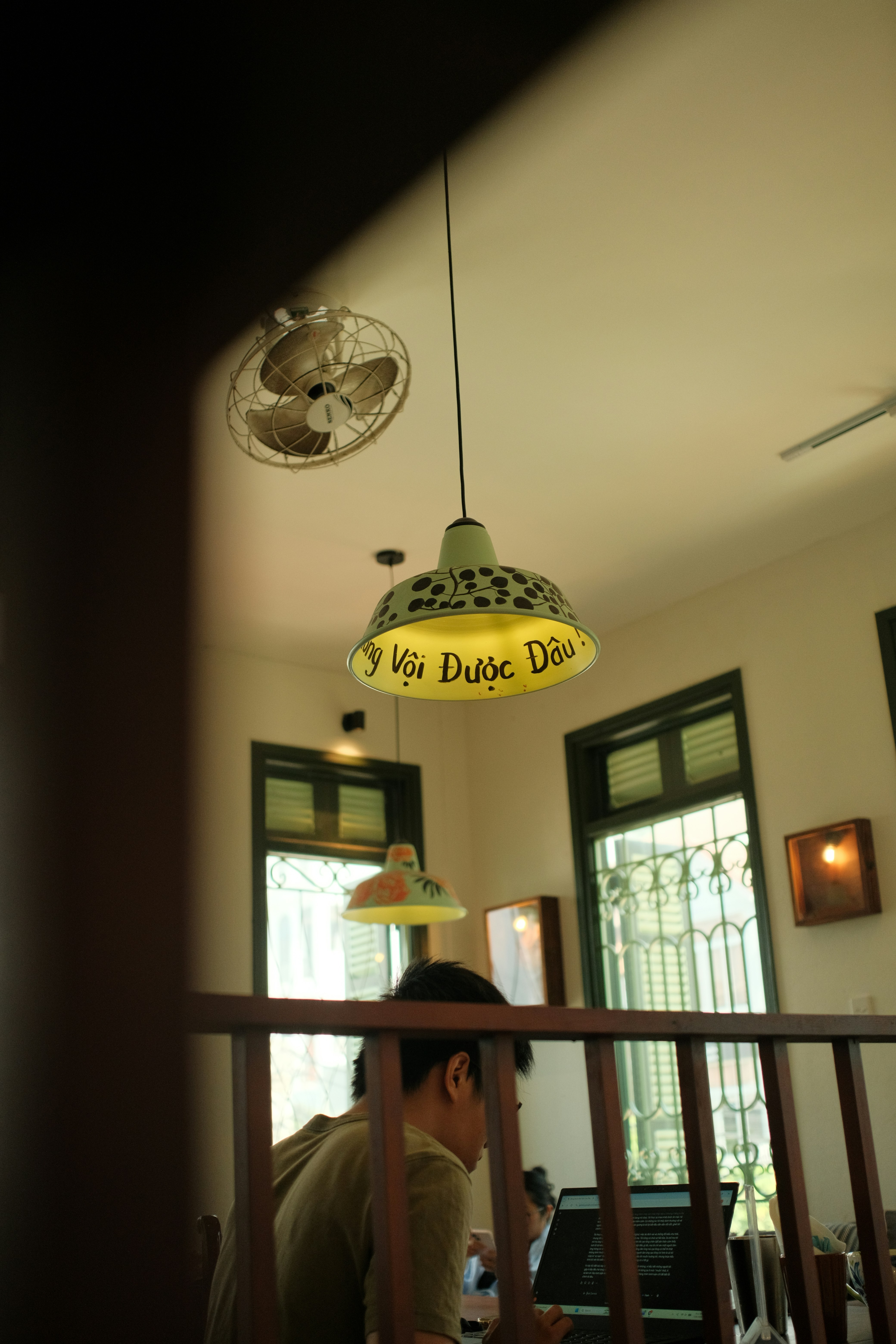 Cafe Interior: Hanging Lamps and Partial Portrait Beyond the Railing