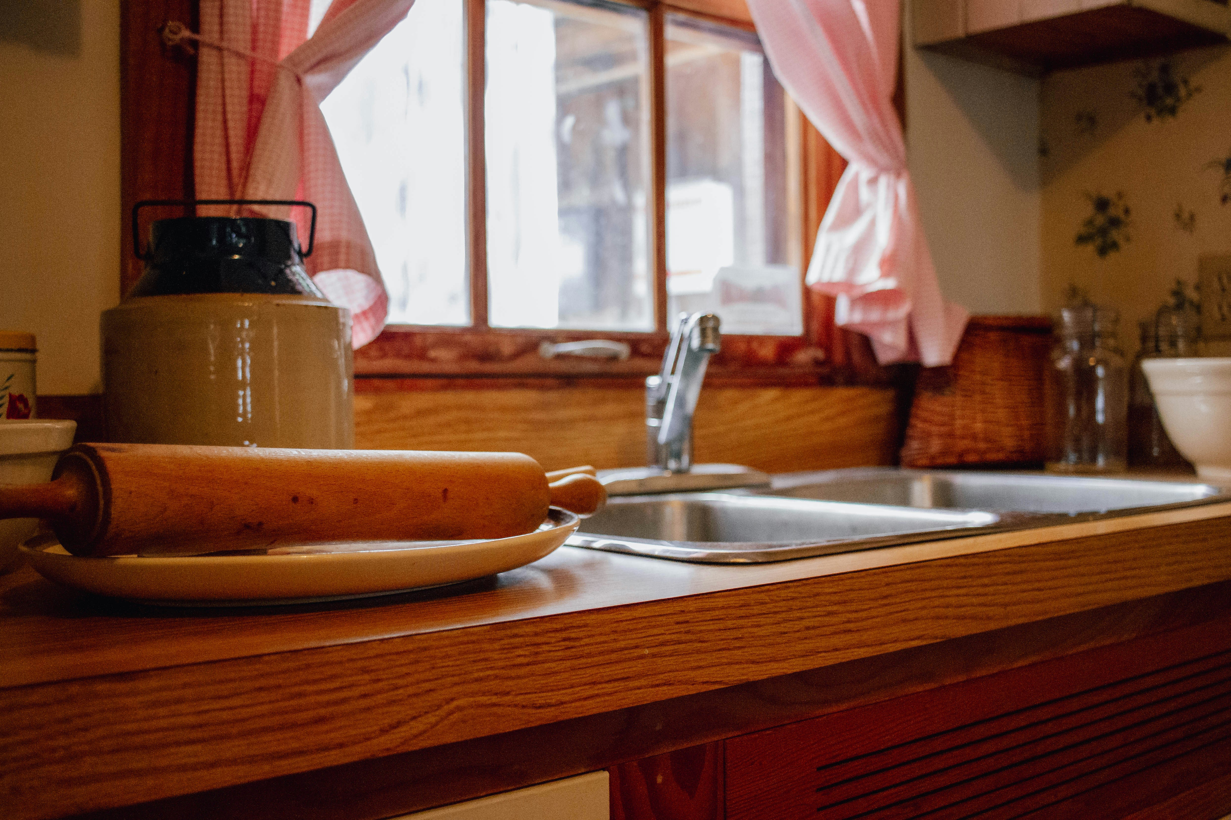 Cozy Dawn in a Rustic Kitchen: Stove, Rolling Pin, and Pink-Curtained Window