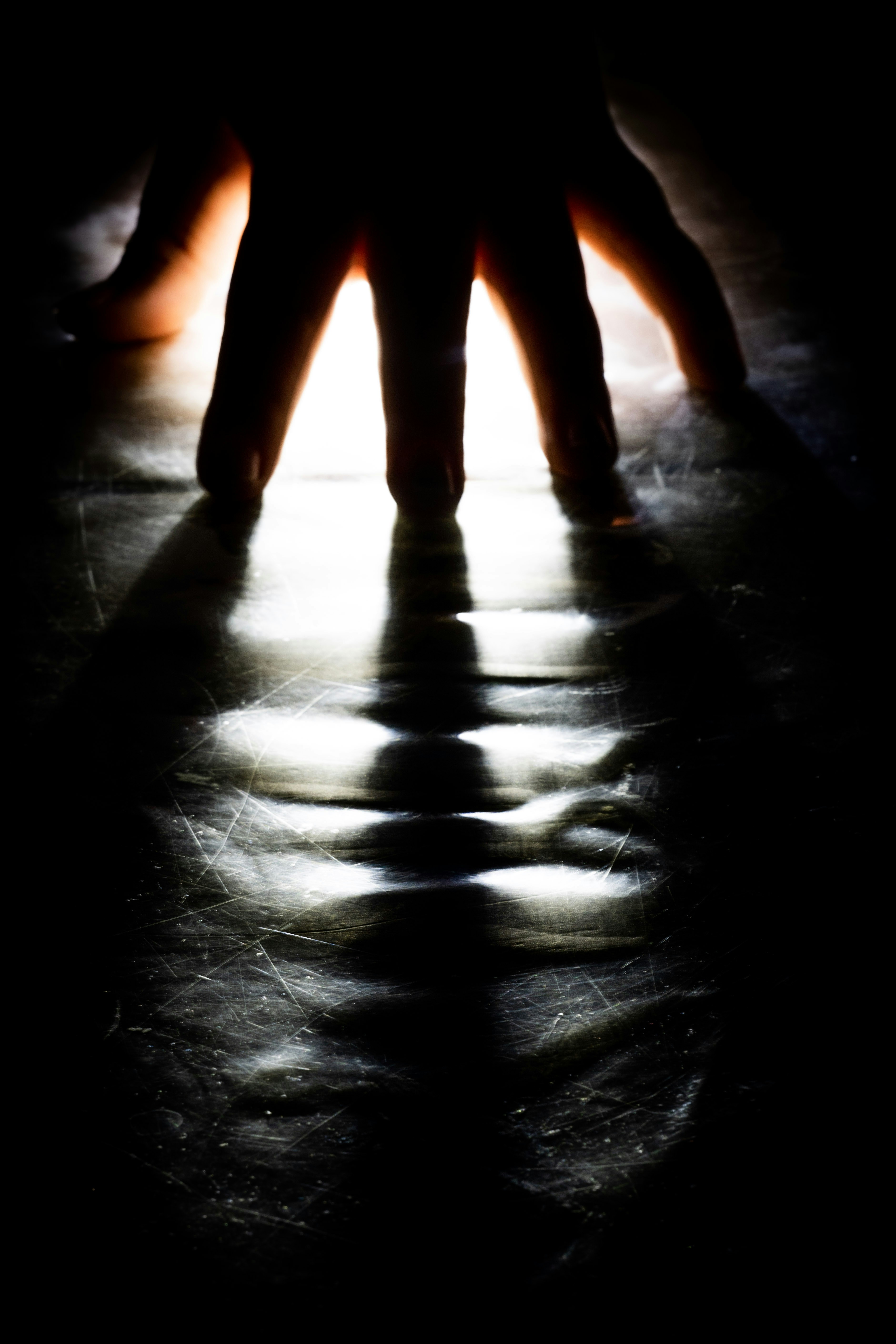 Shadowed Fingers Reach for Light Across a Shiny Surface