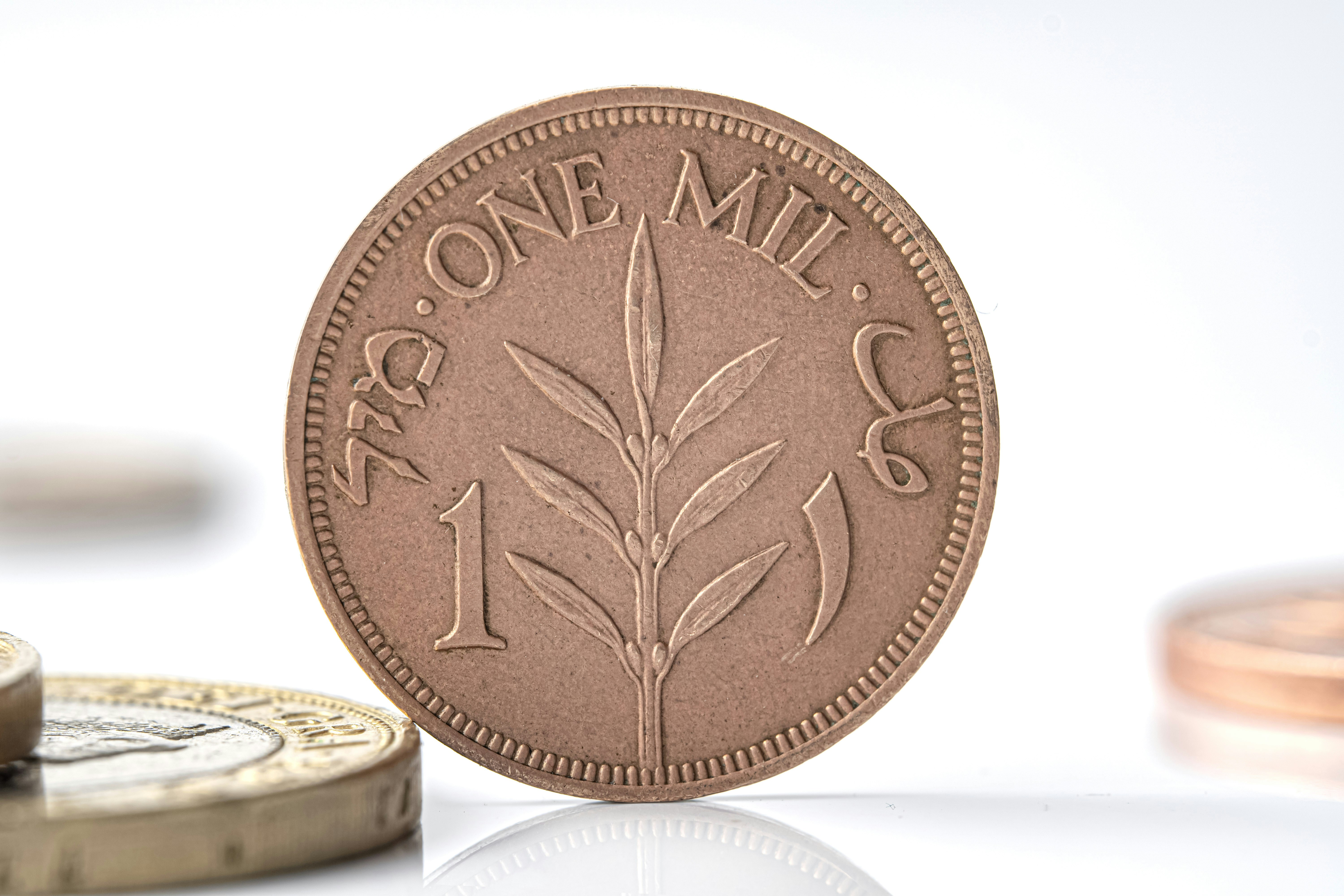 Close-up of a copper coin balancing on a reflective surface