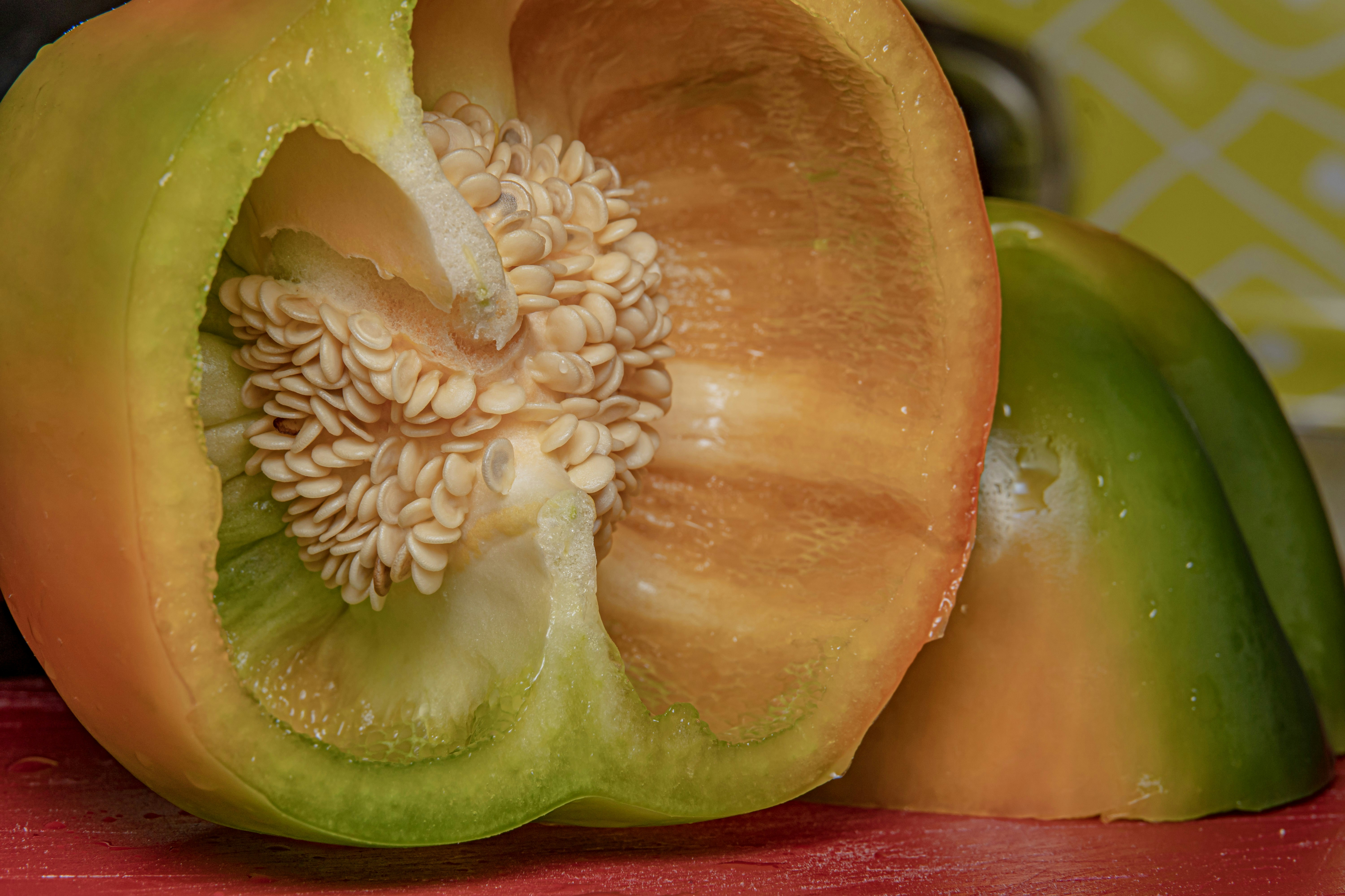 Fragrant Green-Orange Pepper Bloom: Seeds and Texture on a Red Wooden Surface