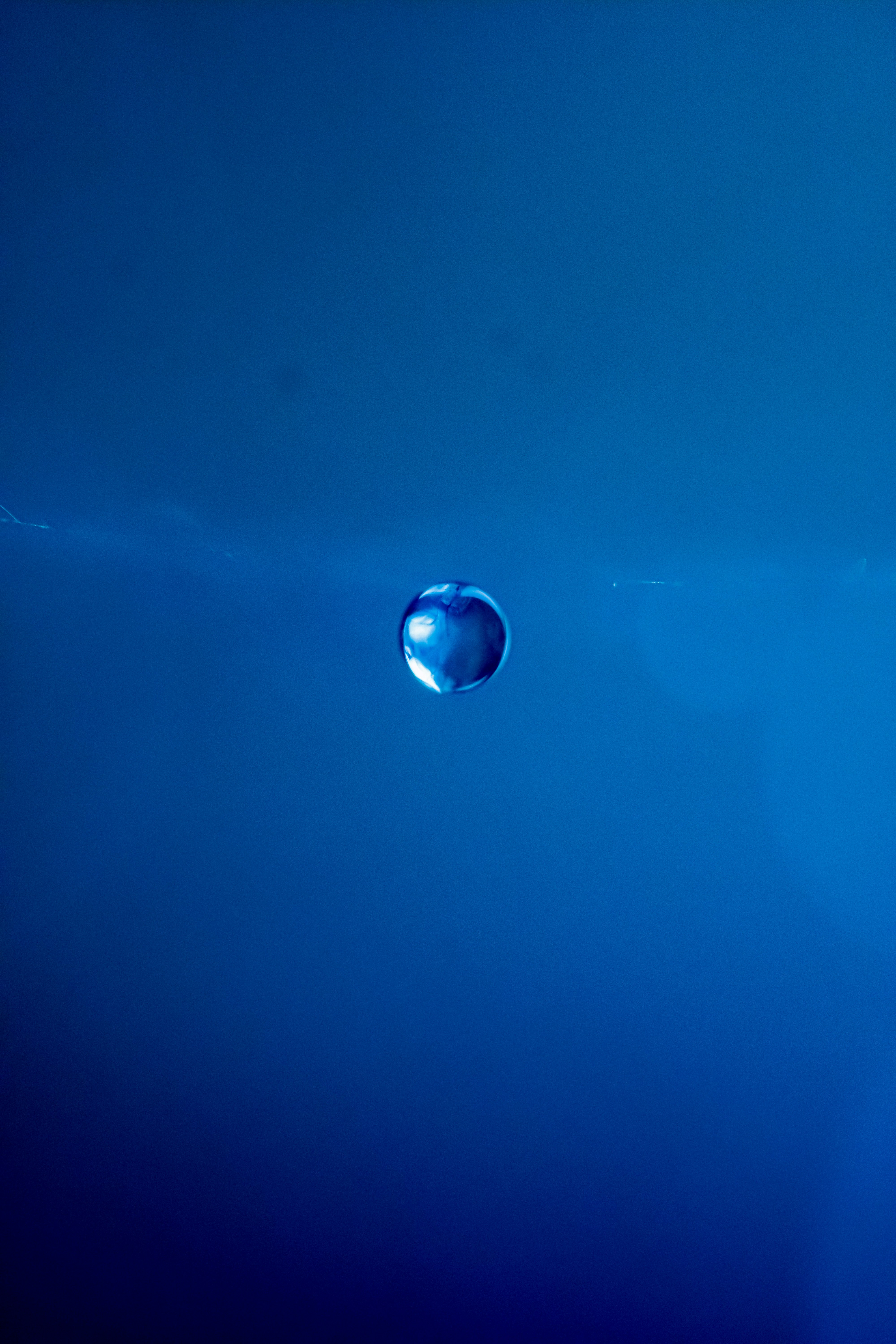 Single blue droplet suspended in a vast cobalt plane