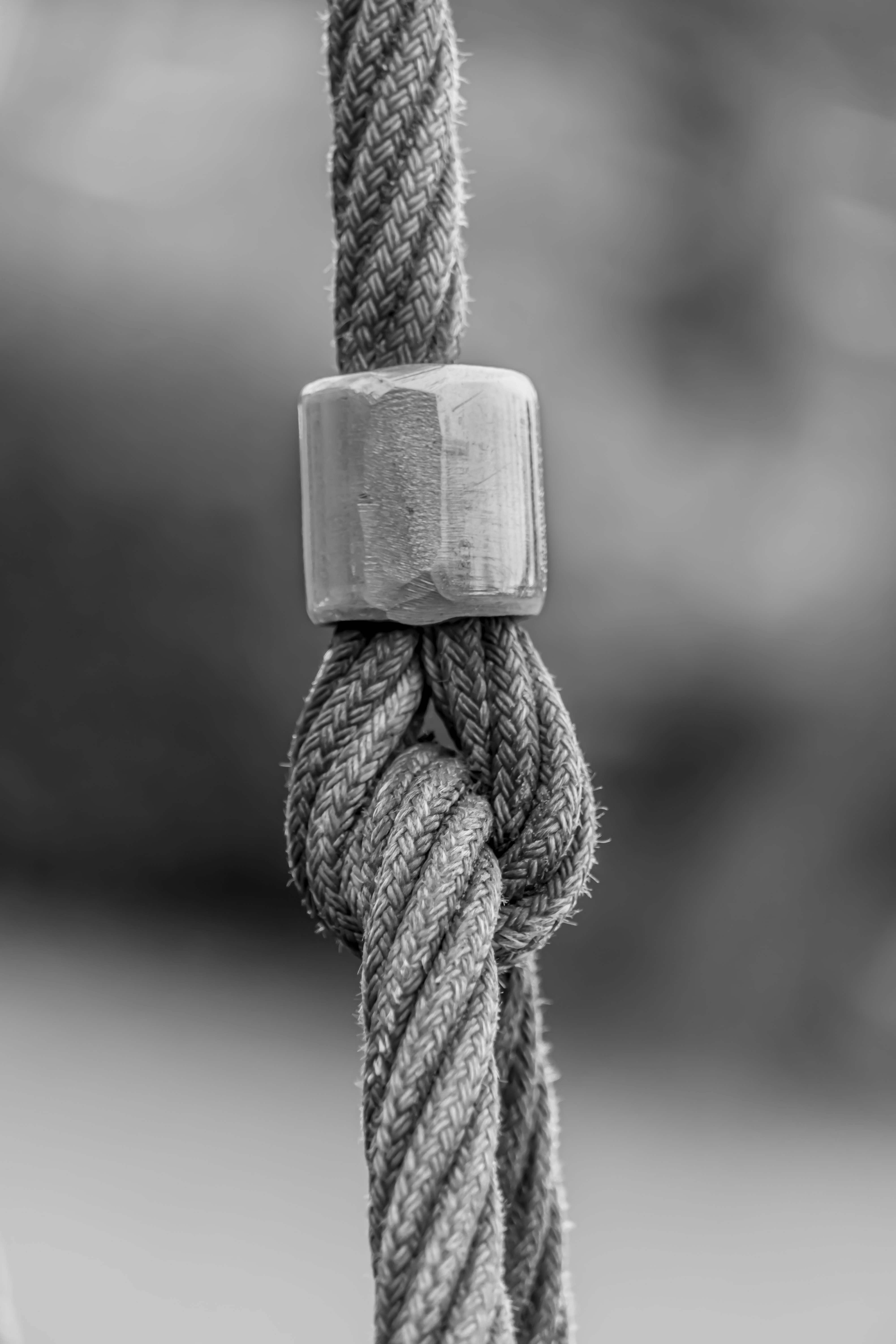 Knot in Focus: A Close-Up of Frayed Rope and Steel Bead