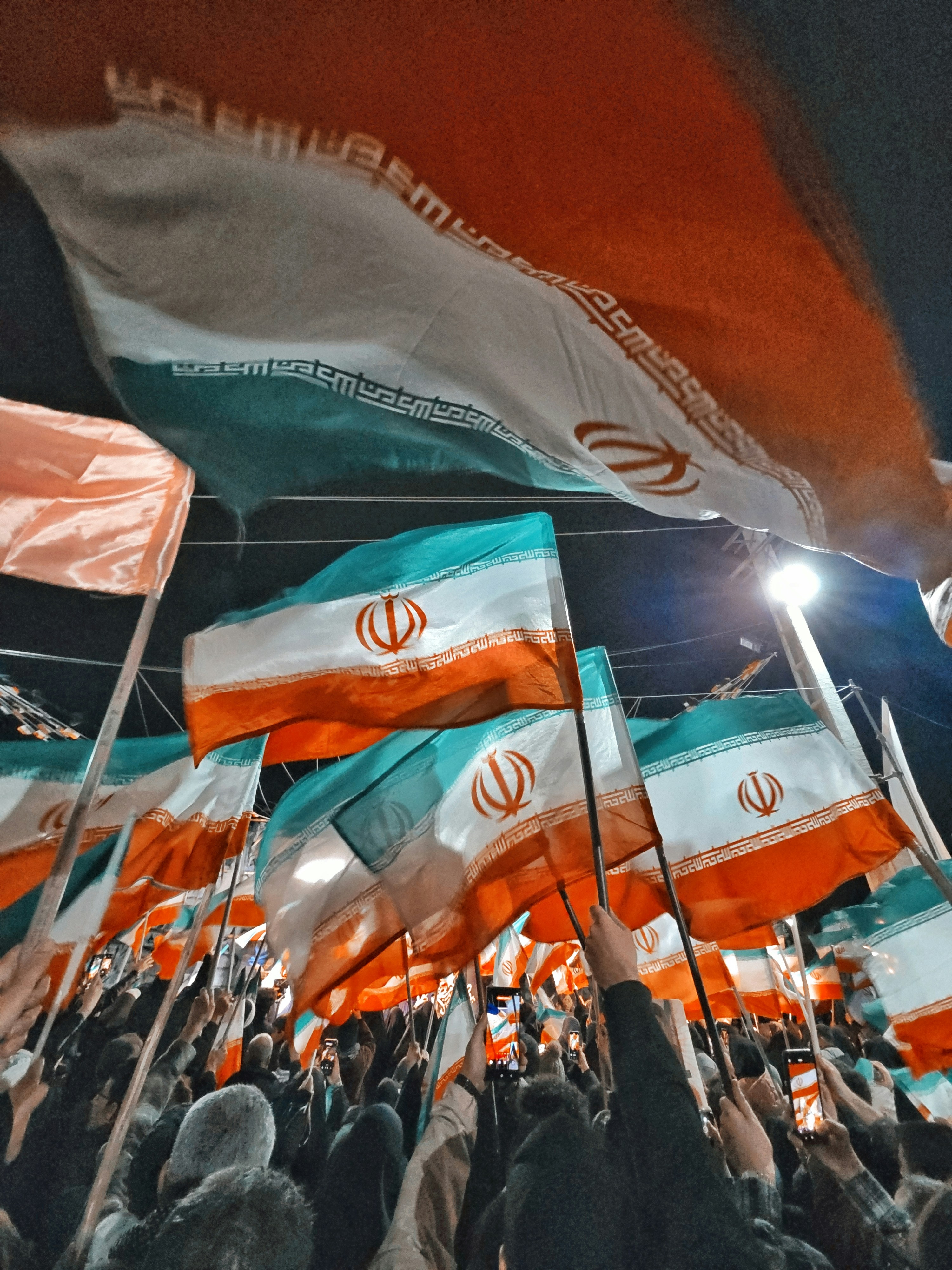 Flags Aloft: A Night Rally of Iran's Tricolor in The Crowd