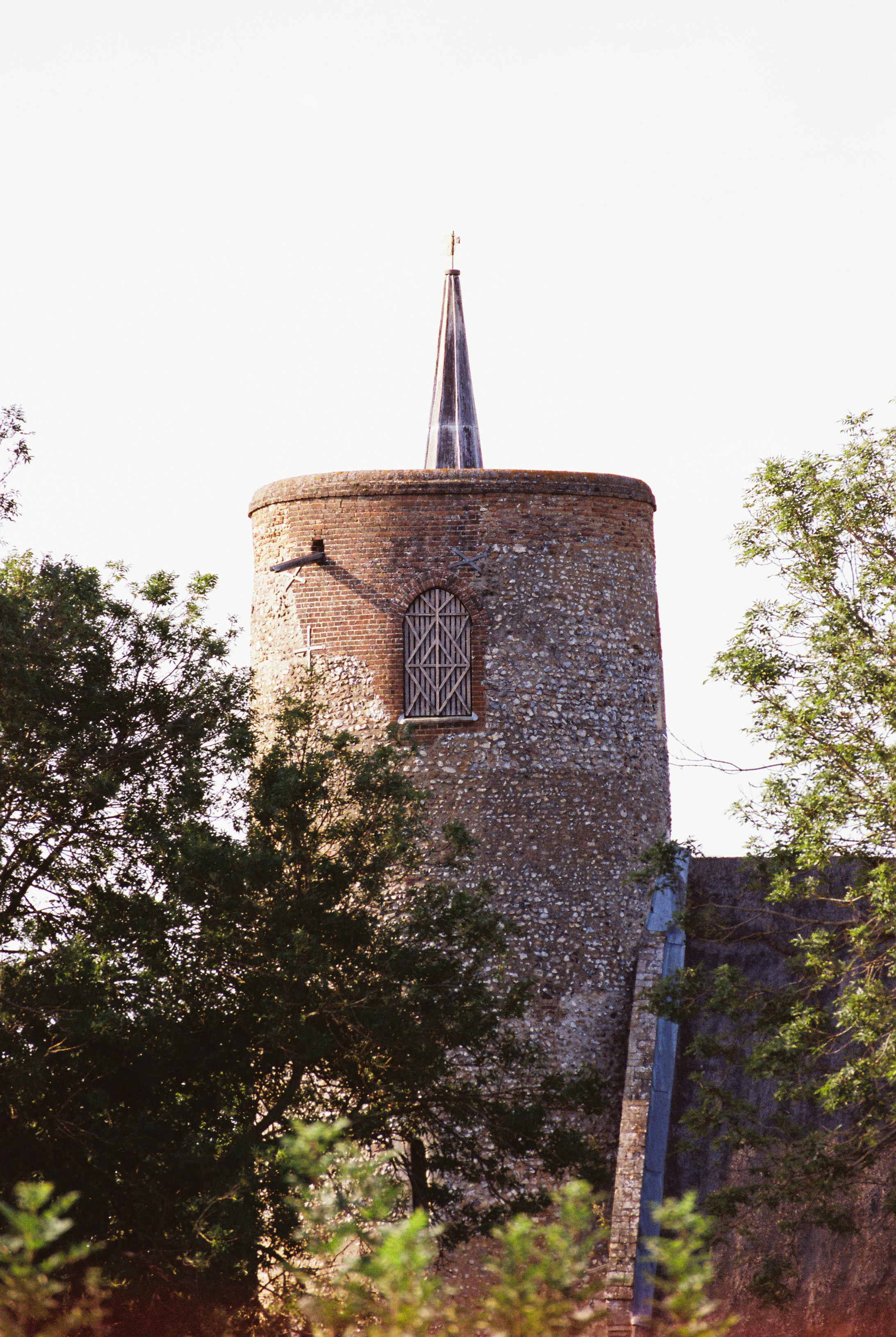 Round Tower Keeper: A Sunlit Brick Sentinel Rising Above Quiet Foliage