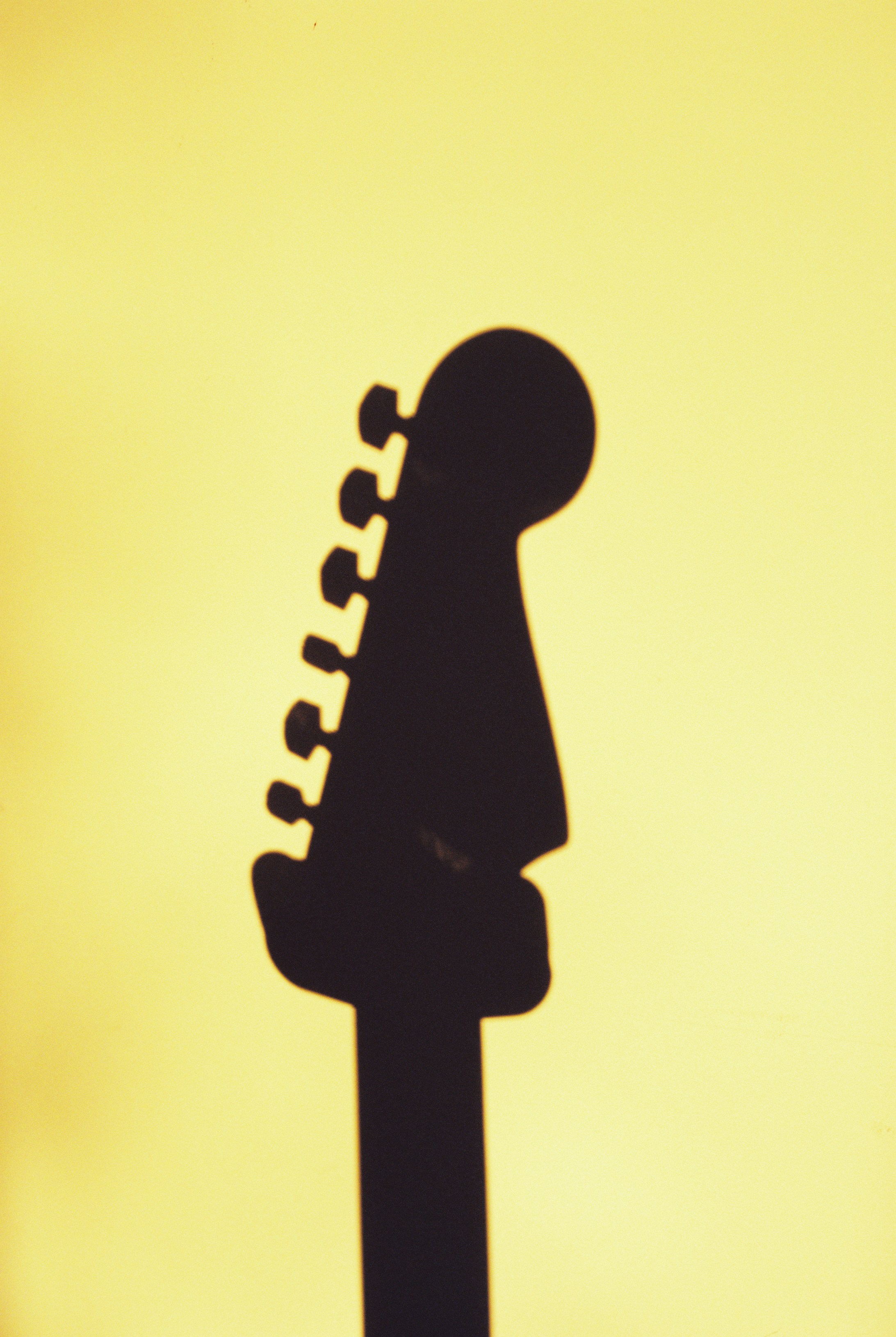 Silhouette of an Electric Dream: Guitar Headstock Against Neon Backdrop