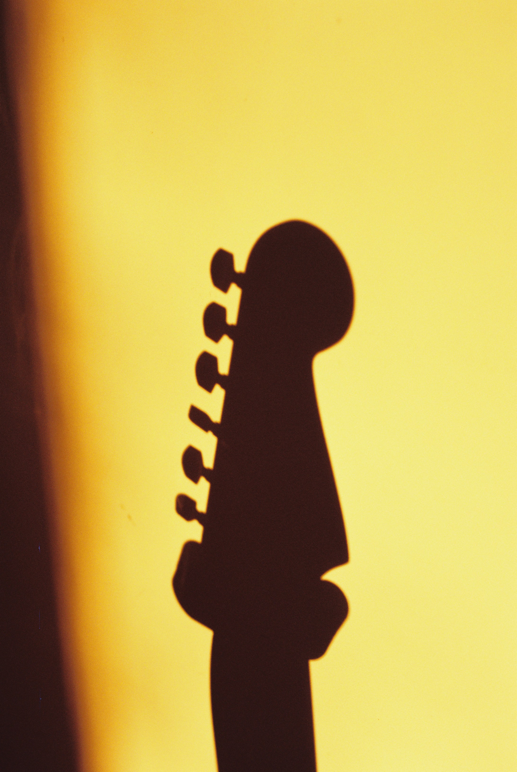 Silhouette of a Guitar Headstock Against Warm Backlight