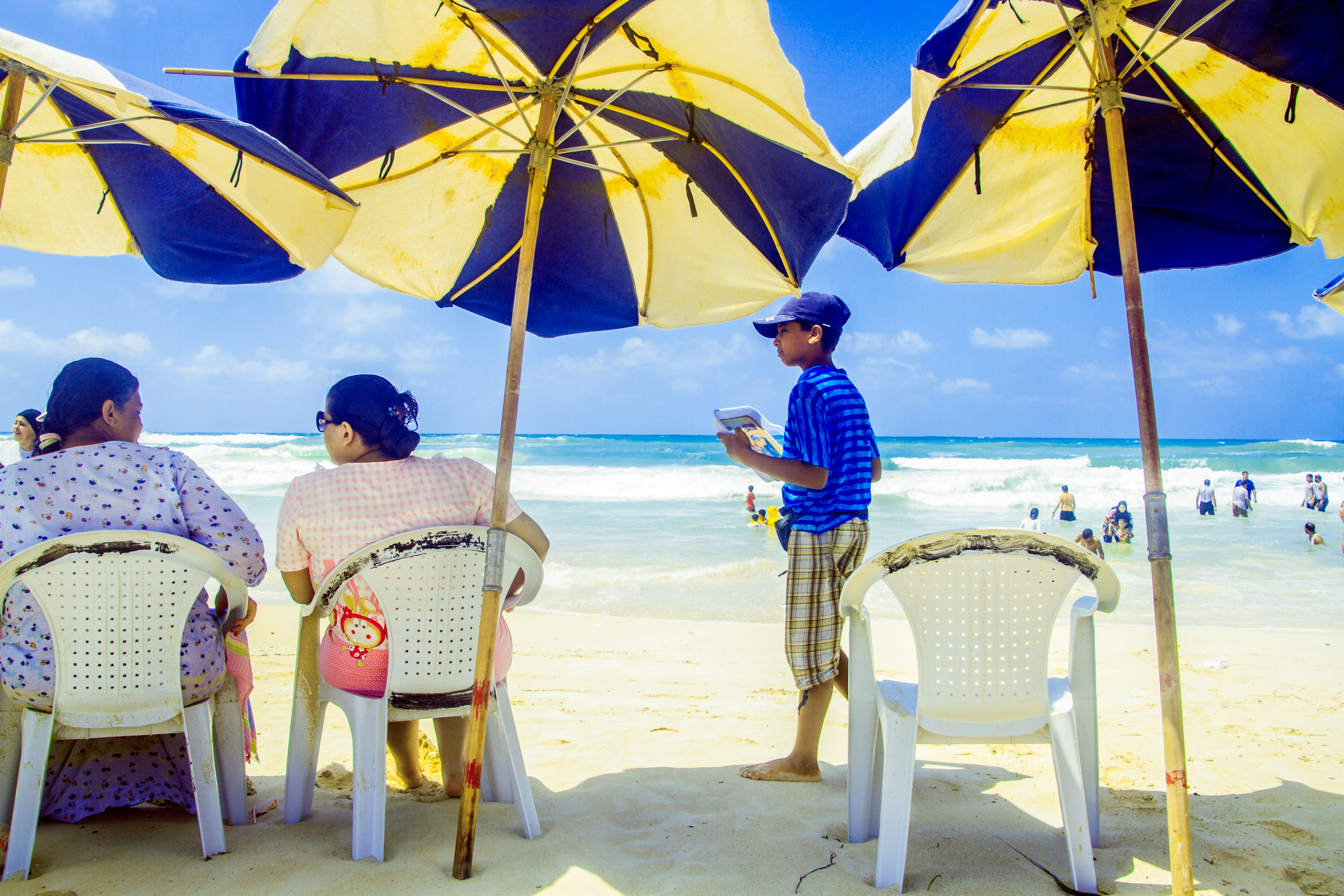 Beachside Reader: A Man in Blue Reads Aloud to a Row of Umbrellas