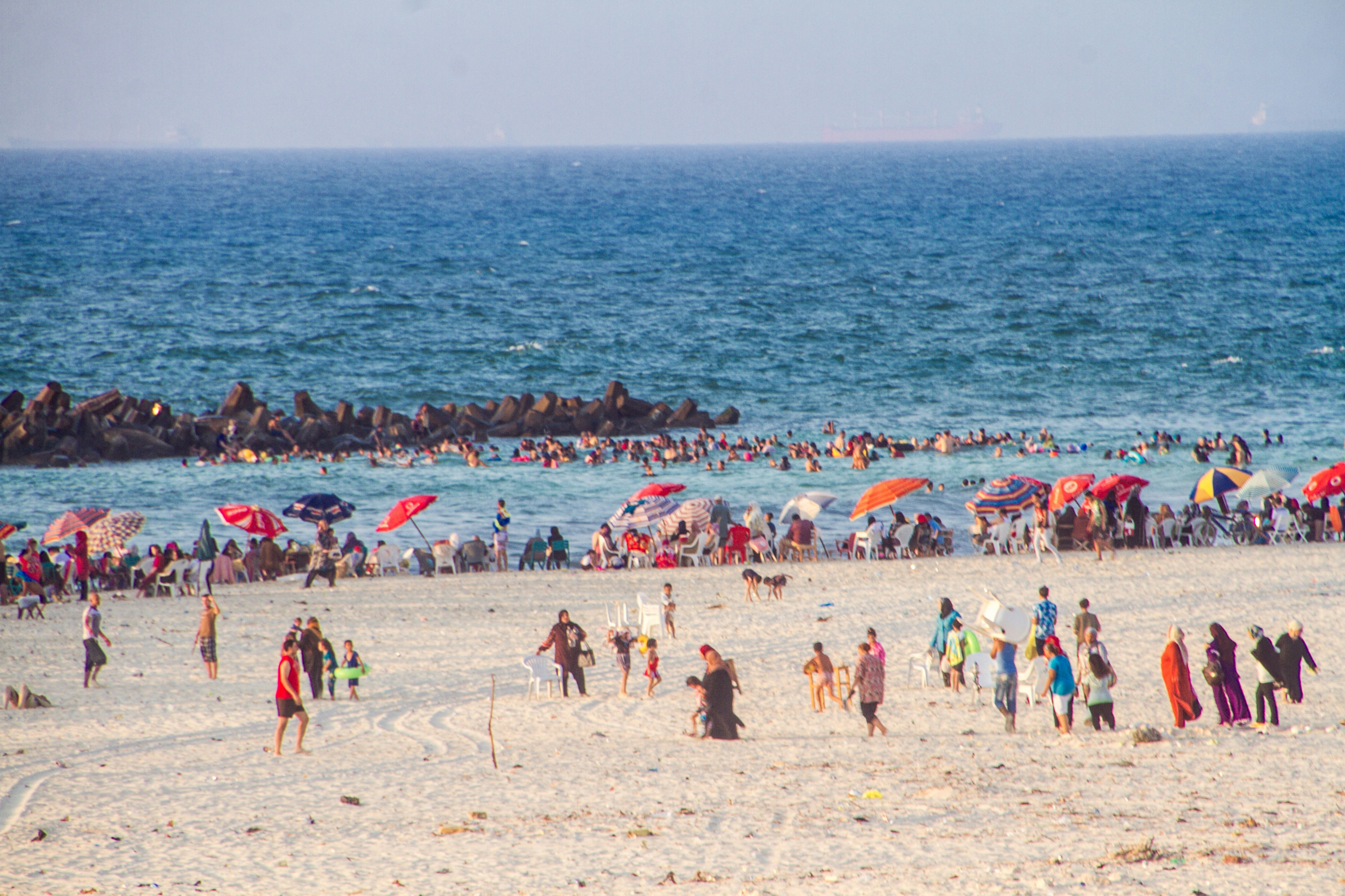 Sunlit Beach Snapshot: Families, Umbrellas, and Lapping Waves