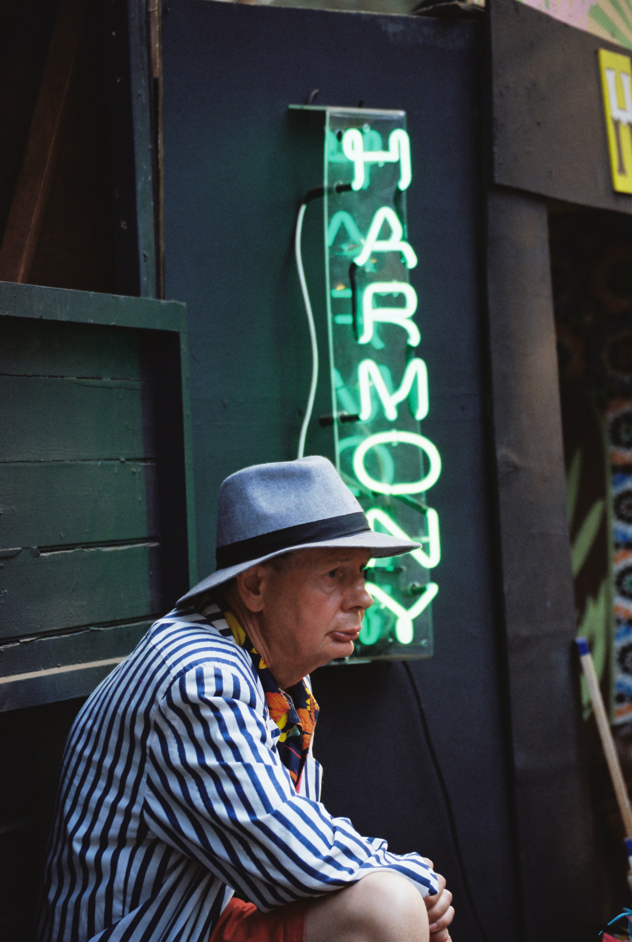 Neon Sign and Striped Portrait: A Quiet Street Moment
