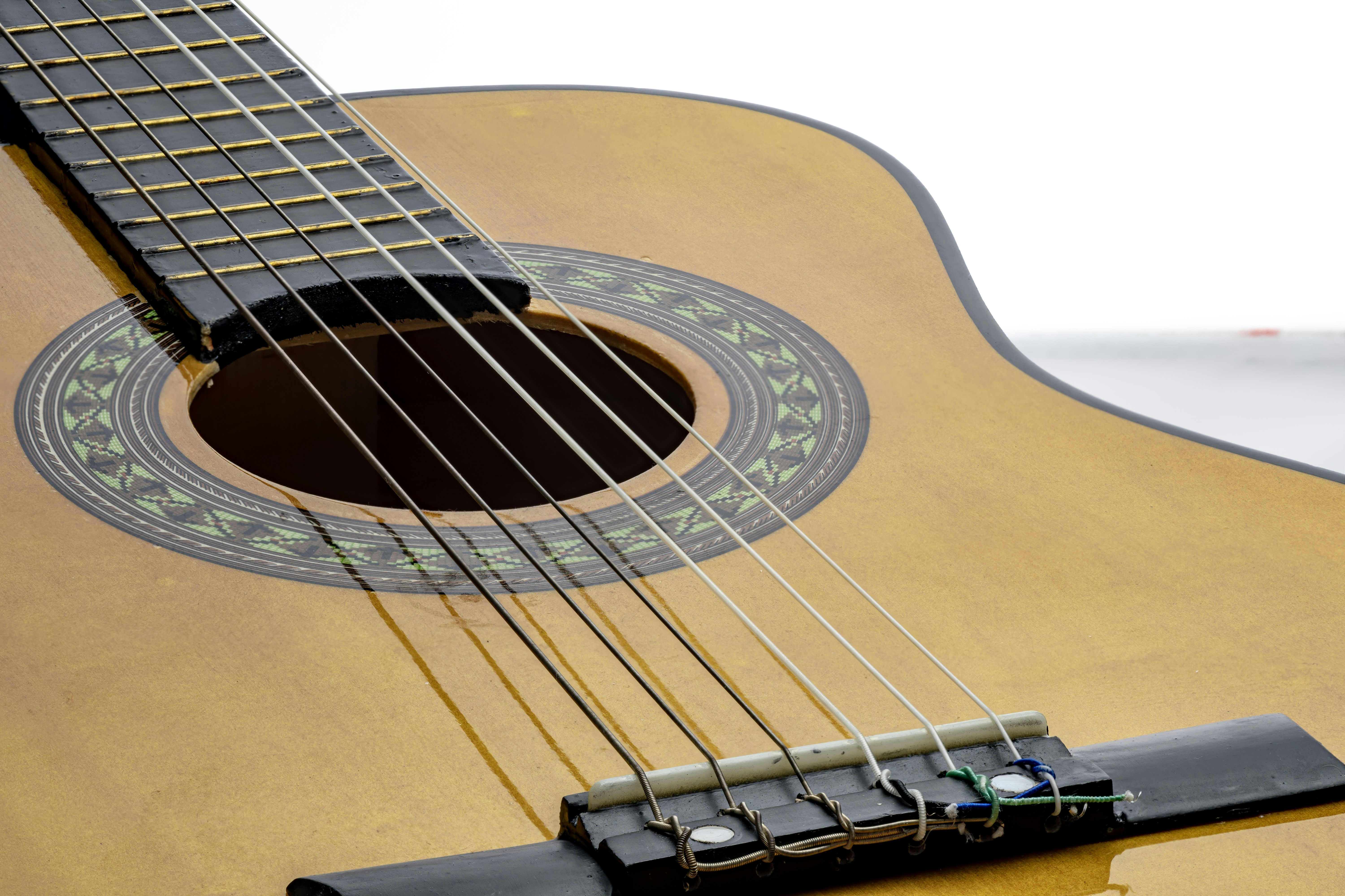 Close-up of a classical guitar's bridge and soundhole with focus on strings and rosette