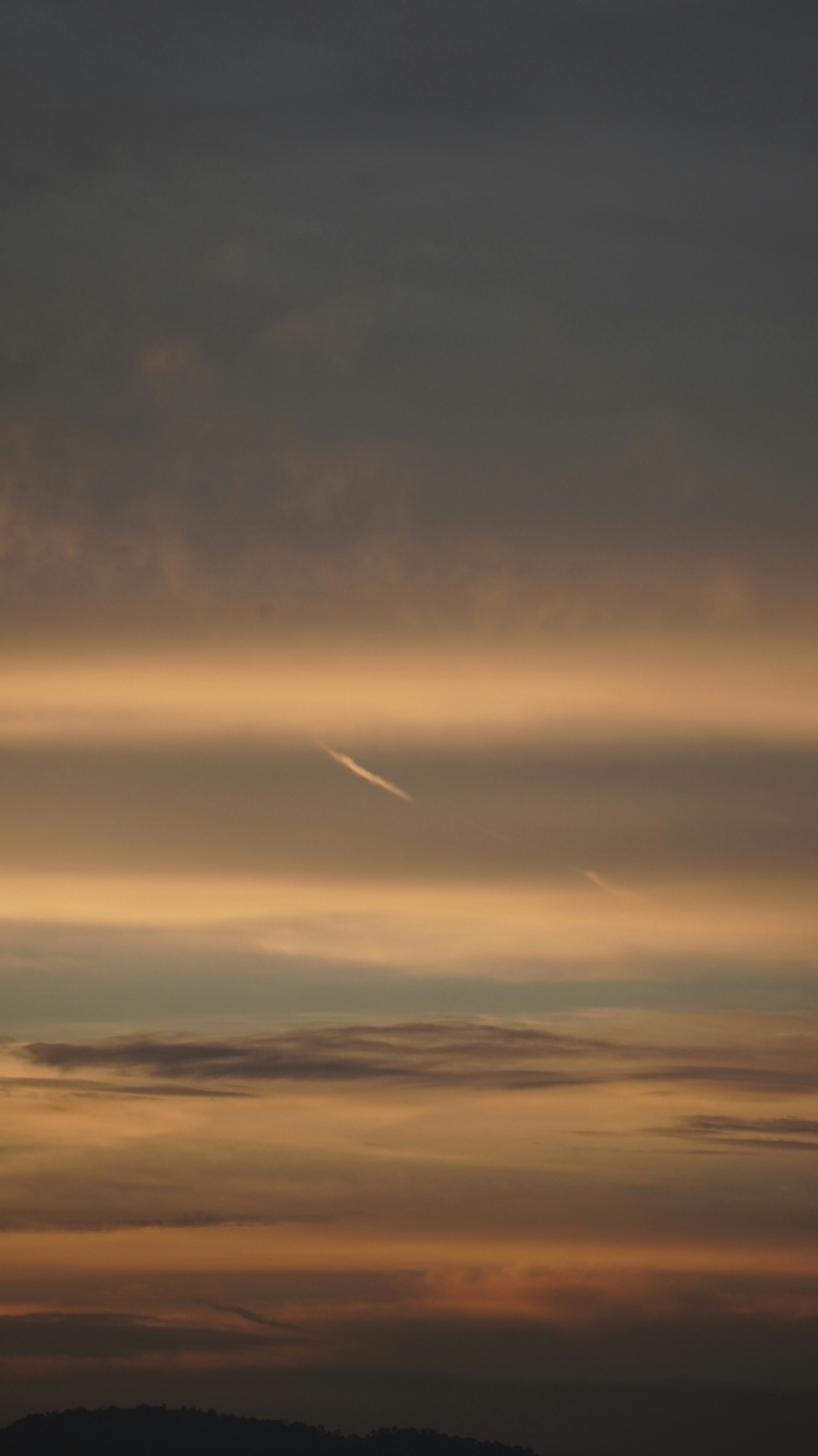 Soft sunset bands spread across the sky with a distant horizon and subtle cloud textures; a calm, expansive landscape emphasizing color gradients. This is a photograph.