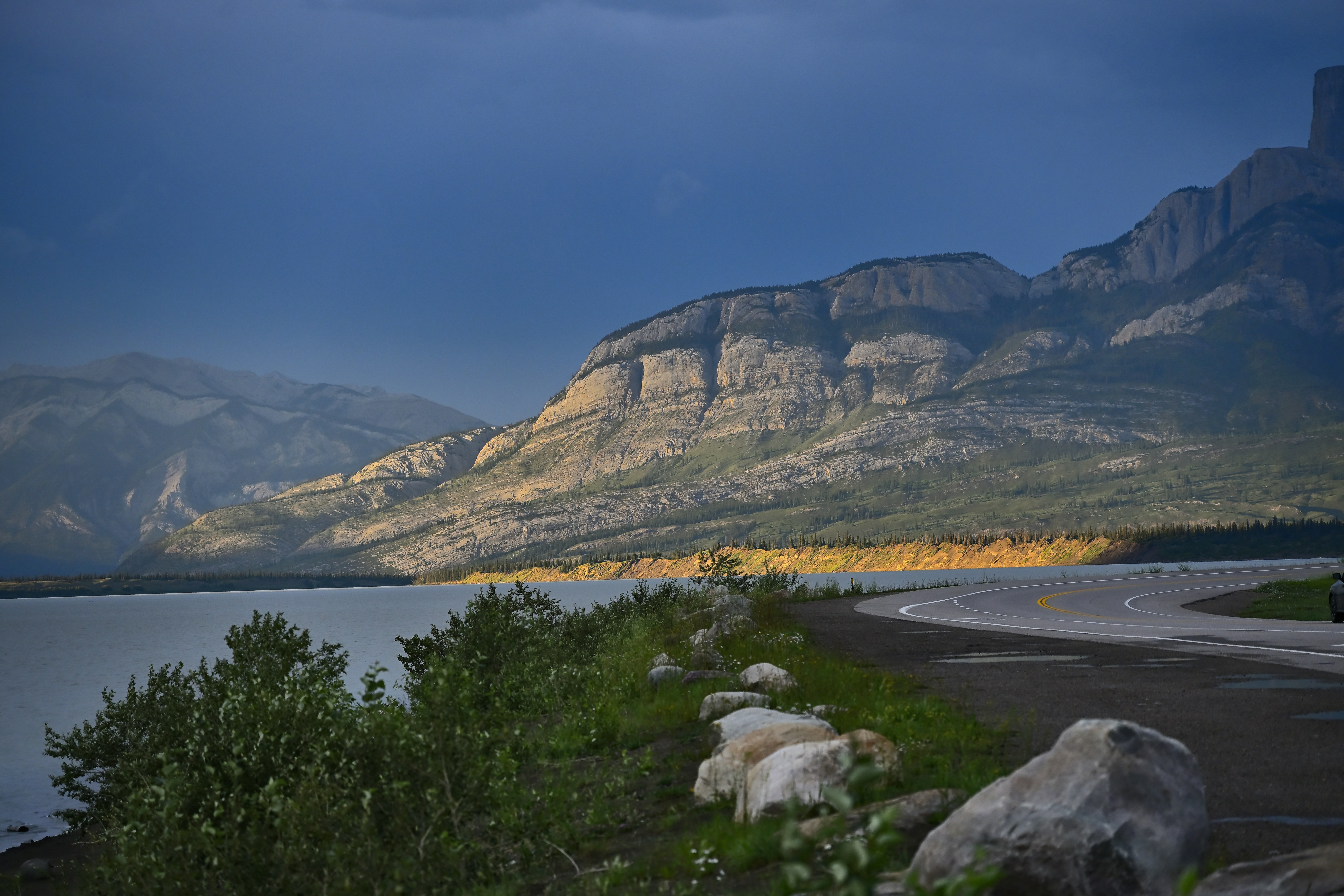 Meandering Road by a Rocky Lake Under Majestic Cliffs
