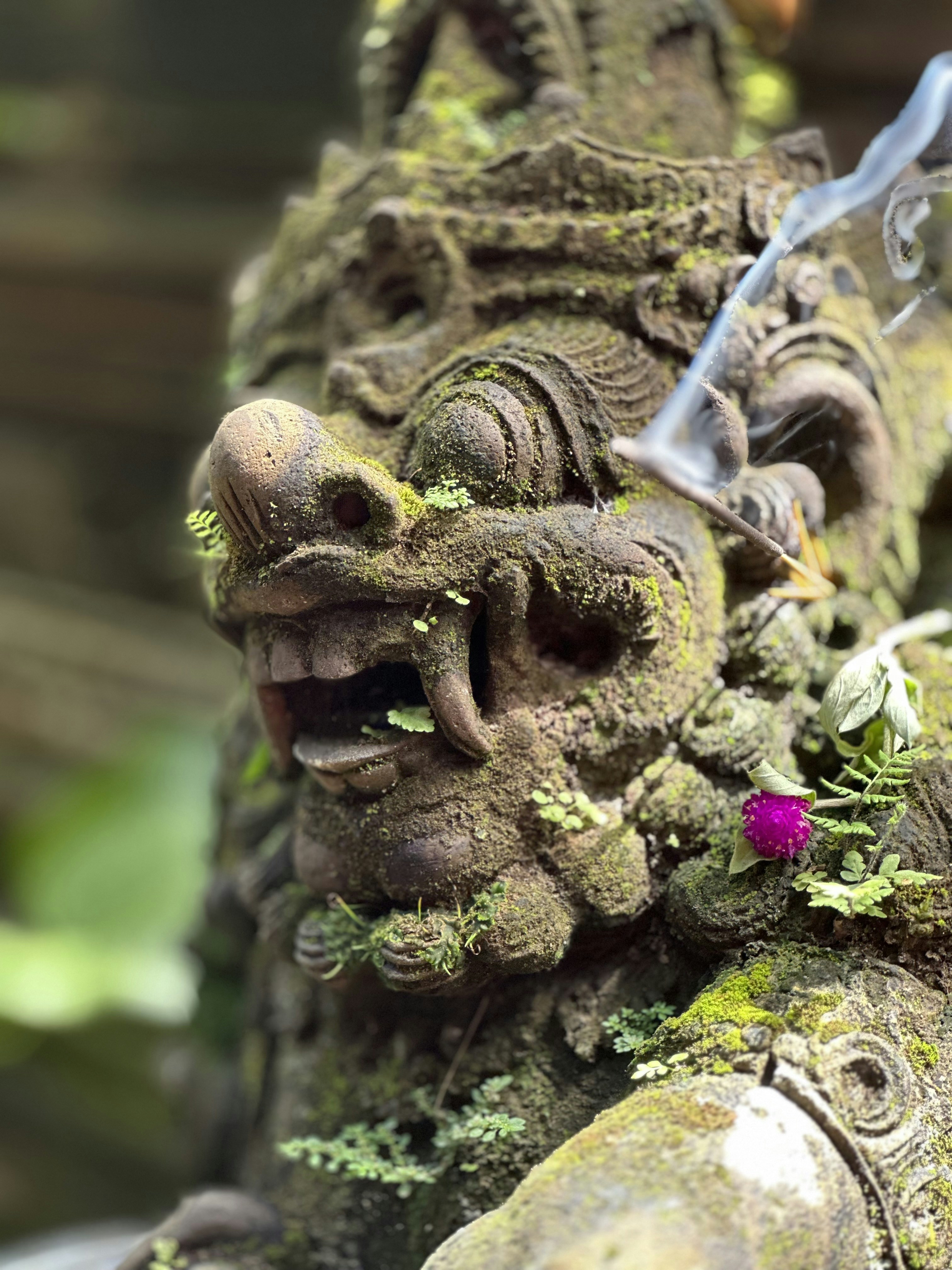 Moss-Crowned Guardian: A Weathered Carving Emerges from Green Veil
