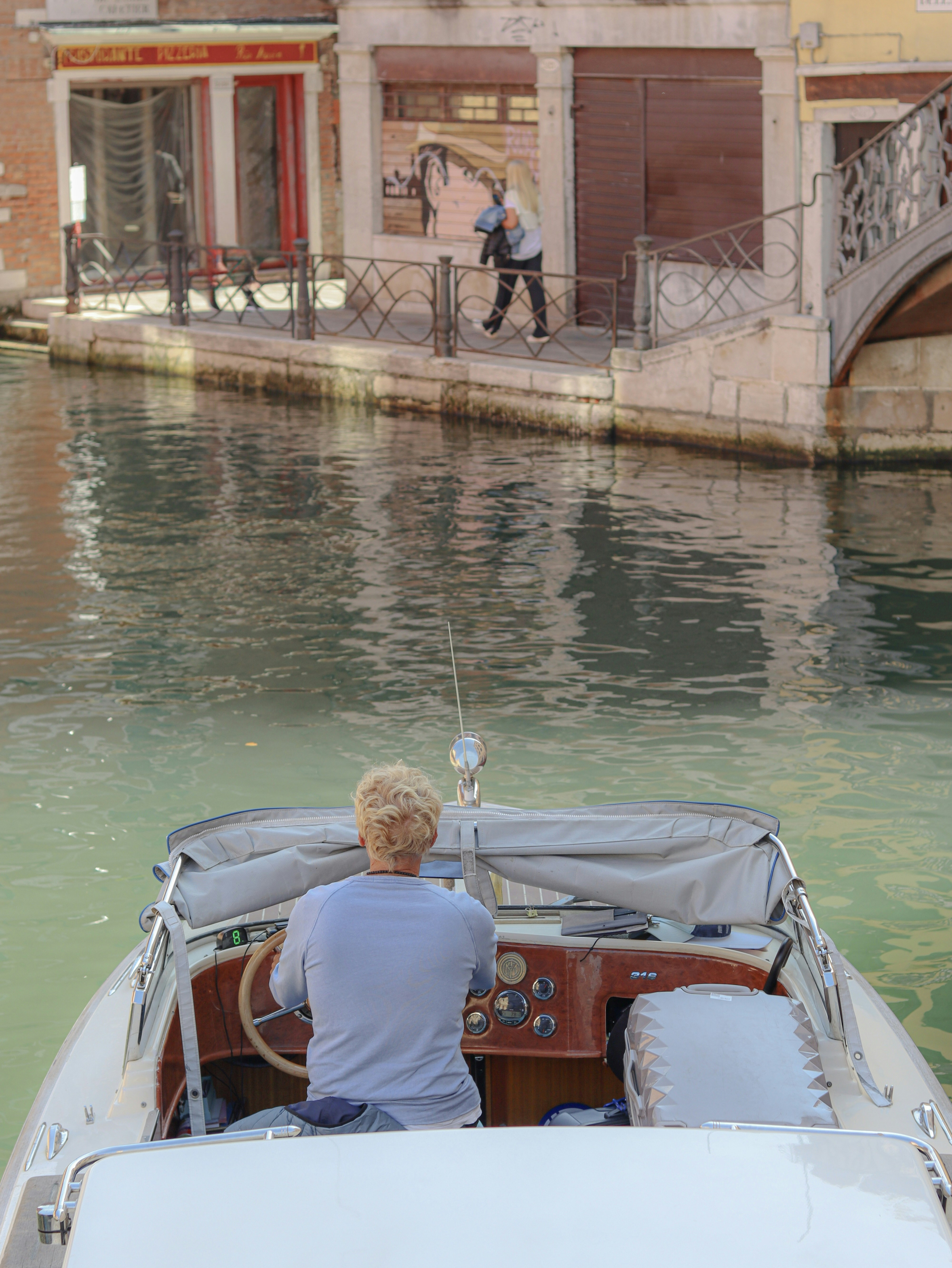 Passenger at the Helm: A Quiet Venice Moment on a Riverside Boat