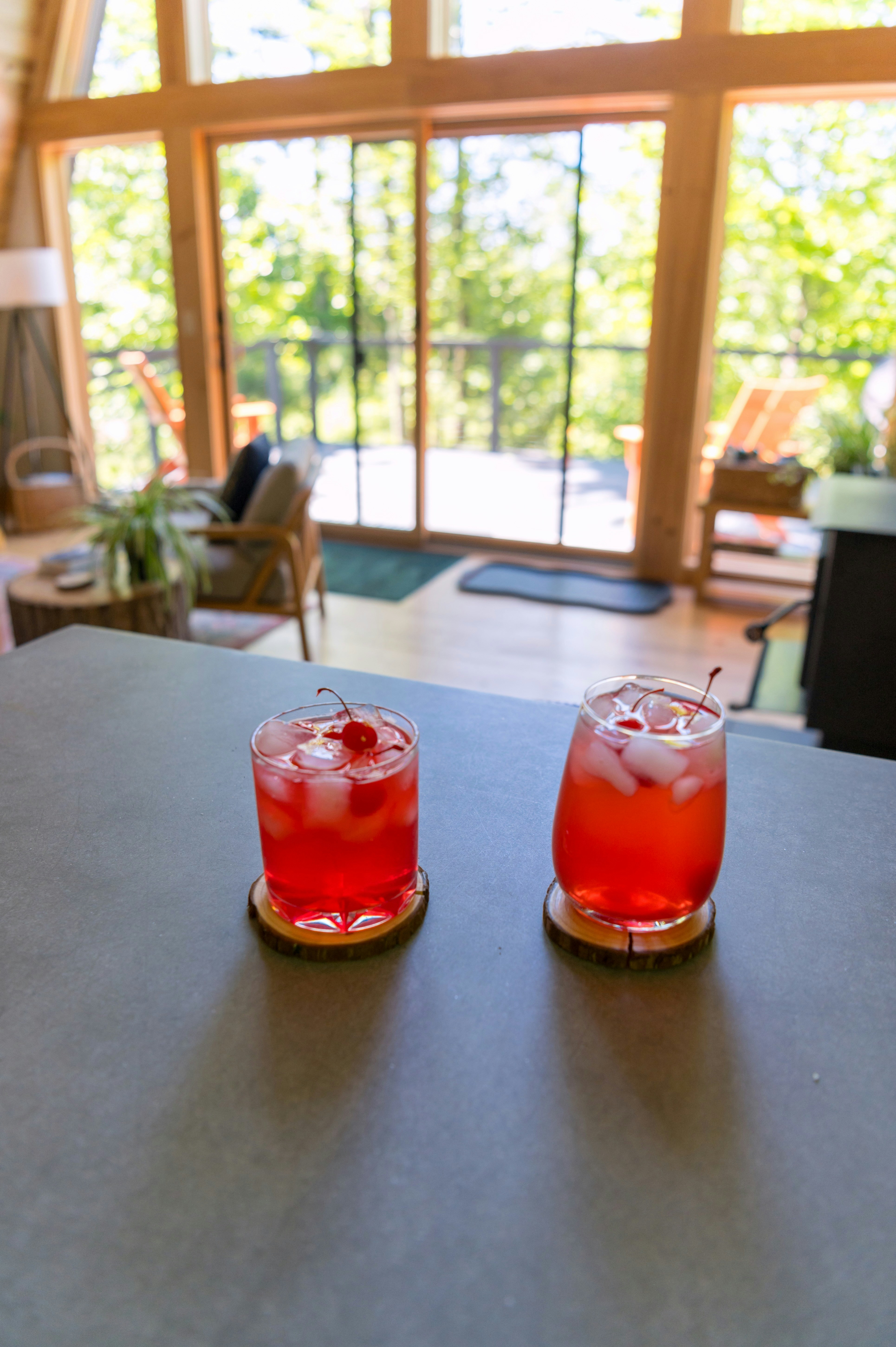 Two Red Cocktails on a Rustic Counter in a Bright Glass-Walled Lounge