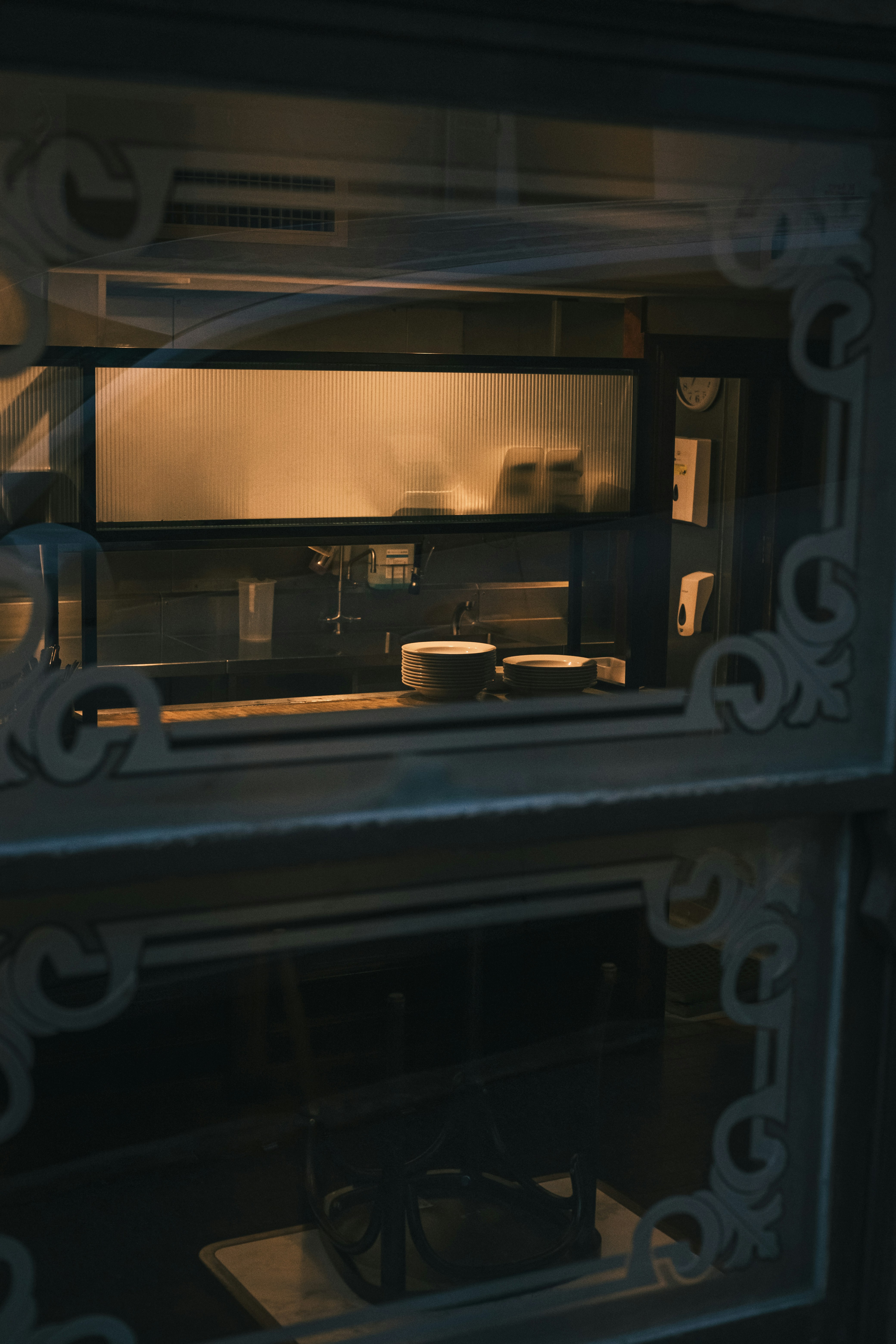 Warm haze in a quiet kitchen through a frosted storefront