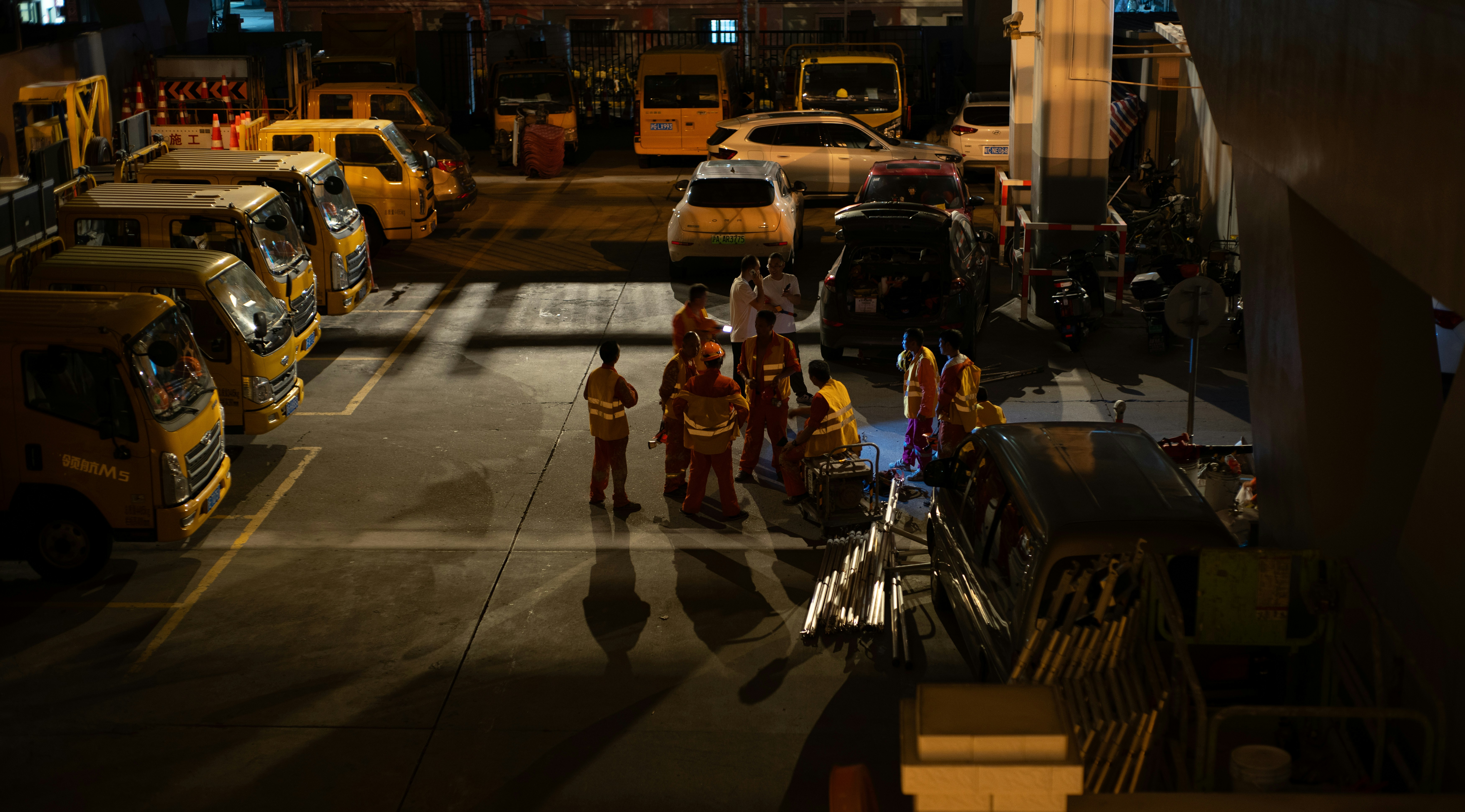 Group of workers near yellow trucks at night.