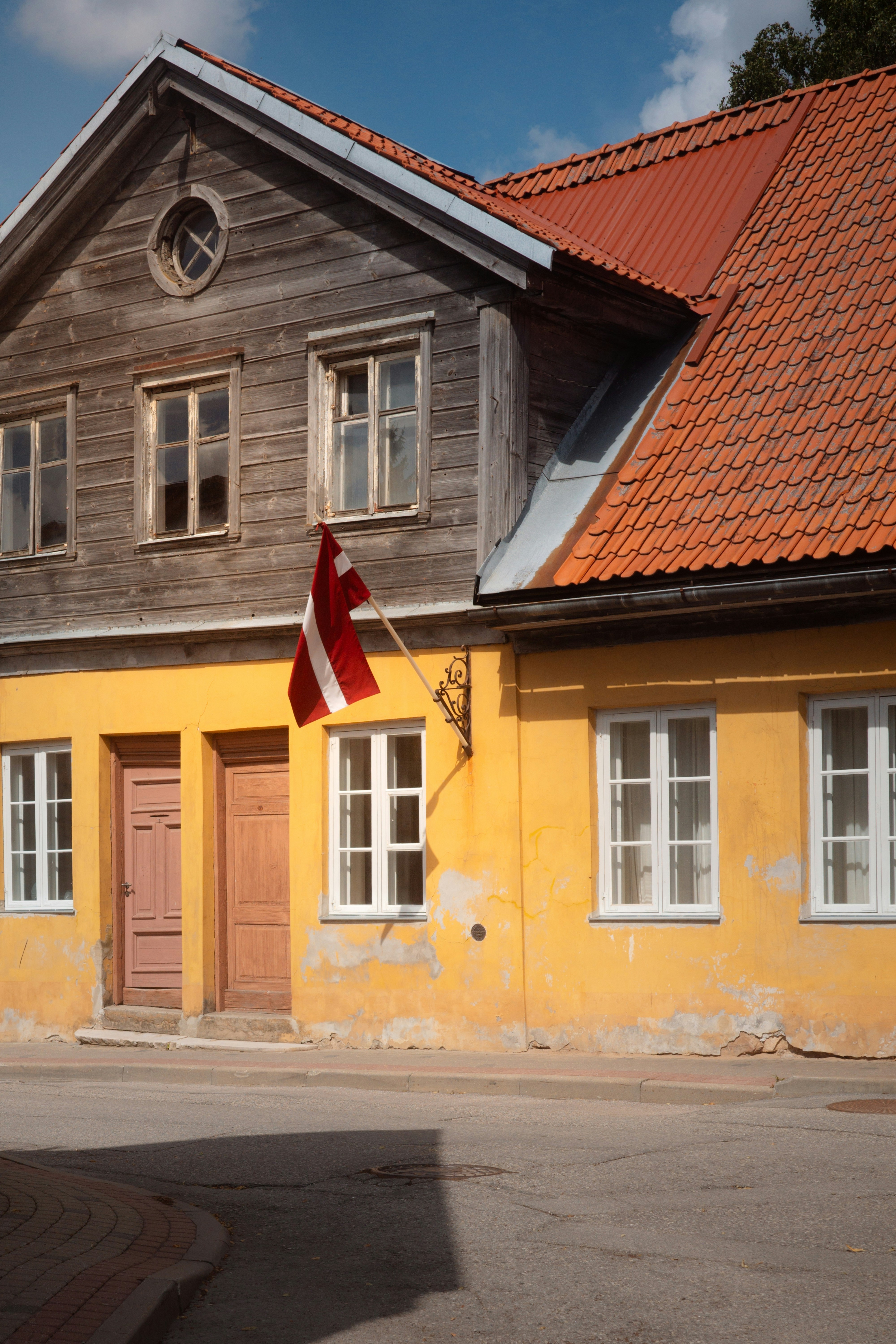 Sunlit Yellow Facade with LV Flag and Weathered Bungalow