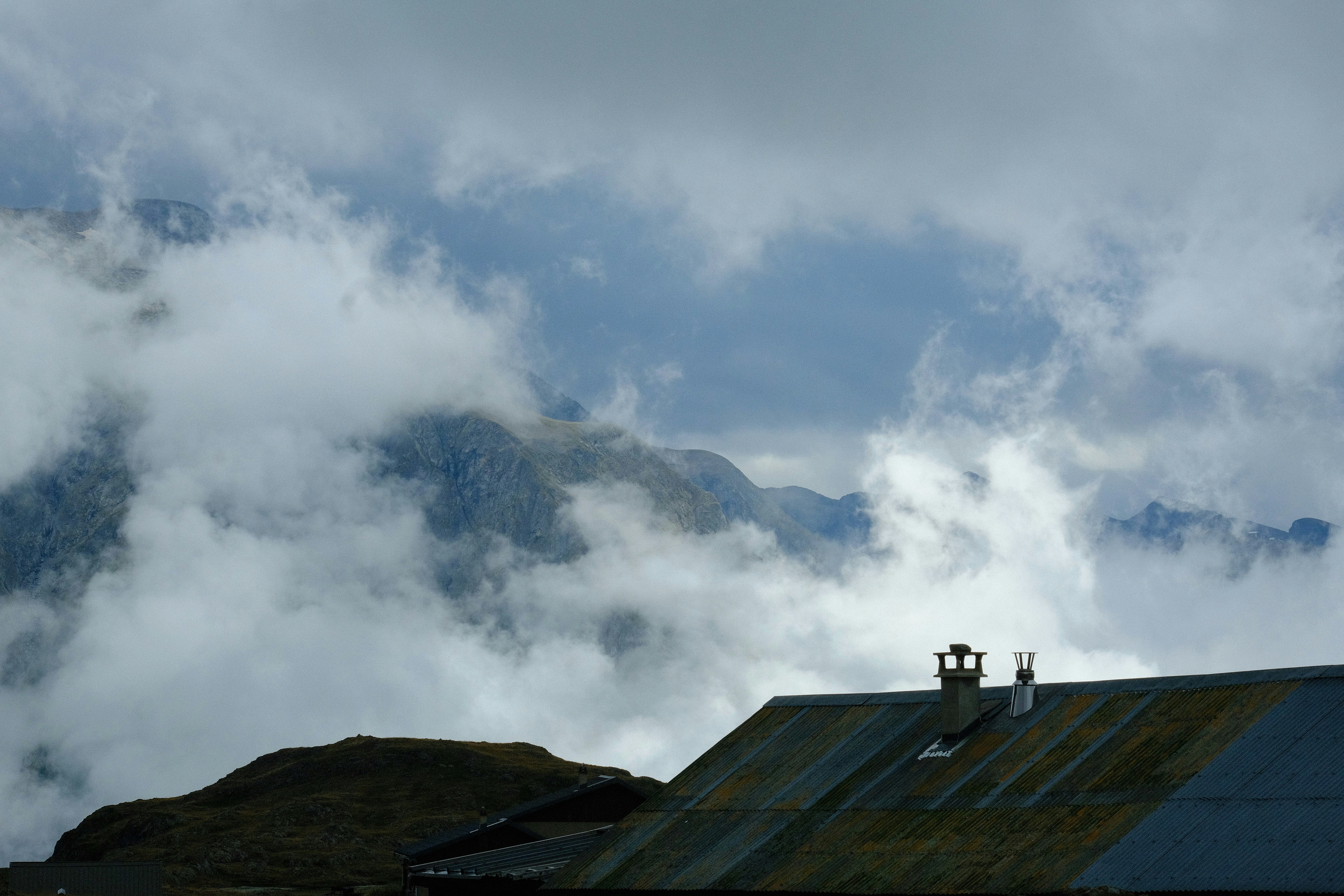 Cloud-veiled Peaks Over a Weathered Roof