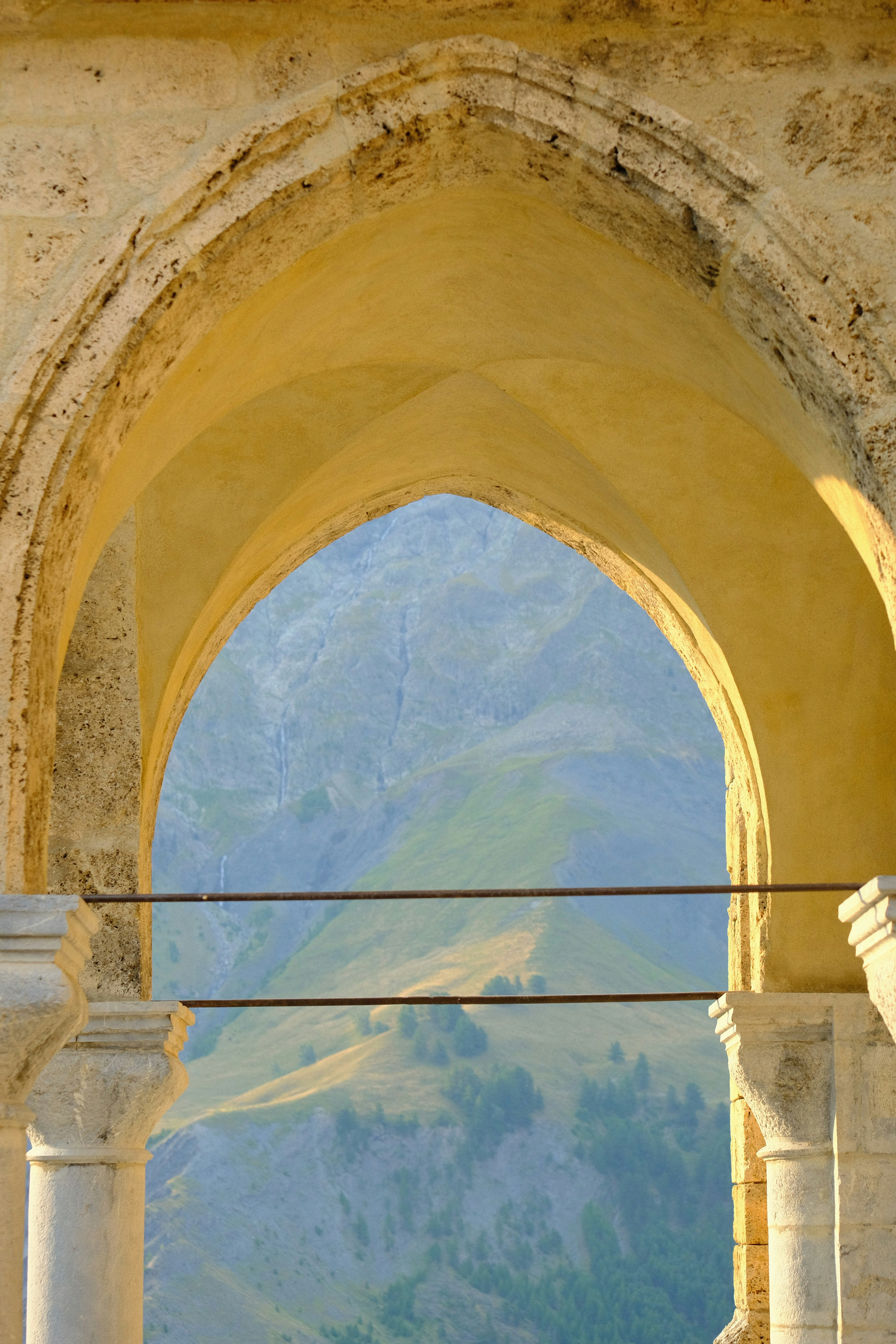Archway to Alpine Light: Framed Valley Through Stone Weave