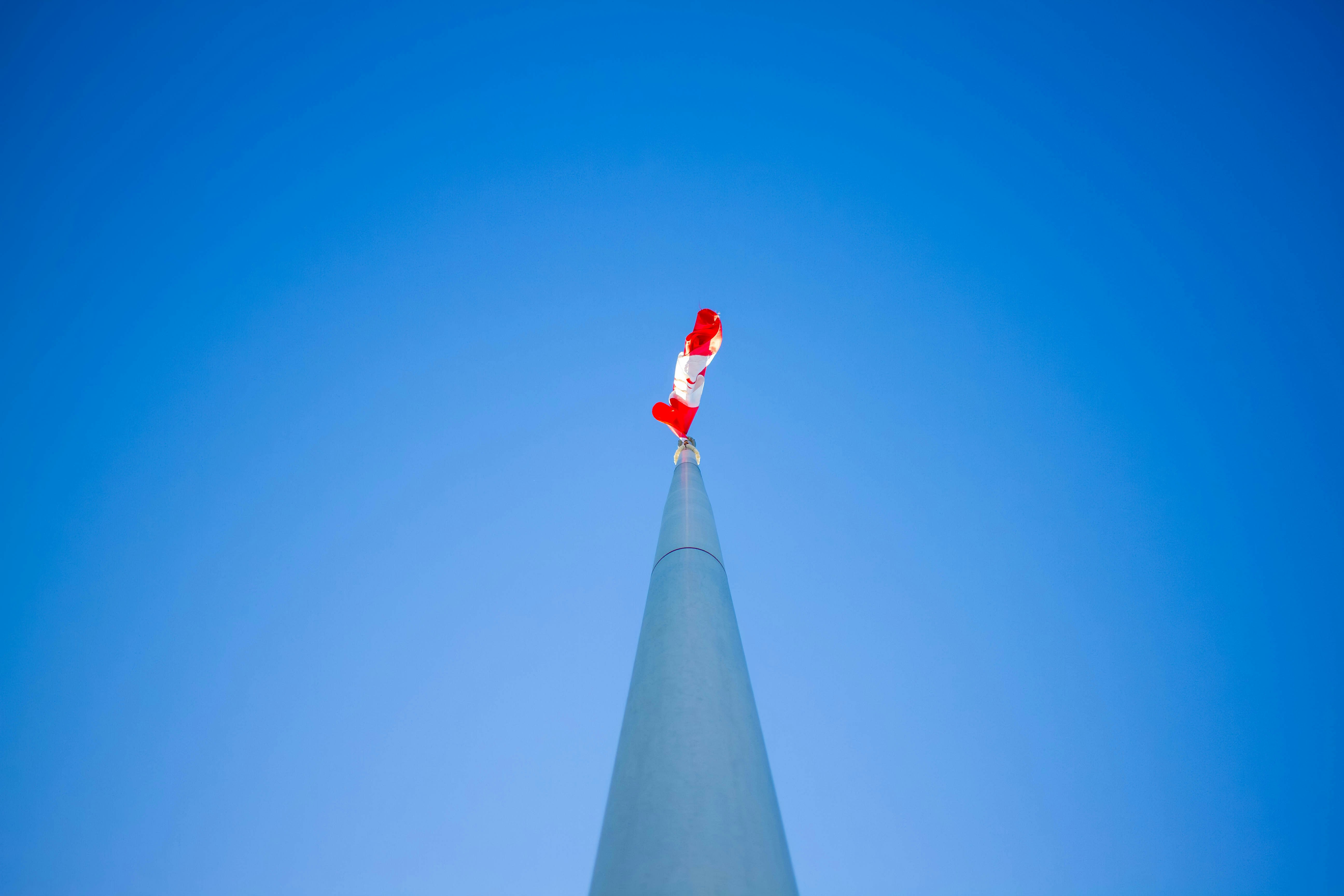 Flag atop a tapering spire under a clear blue sky