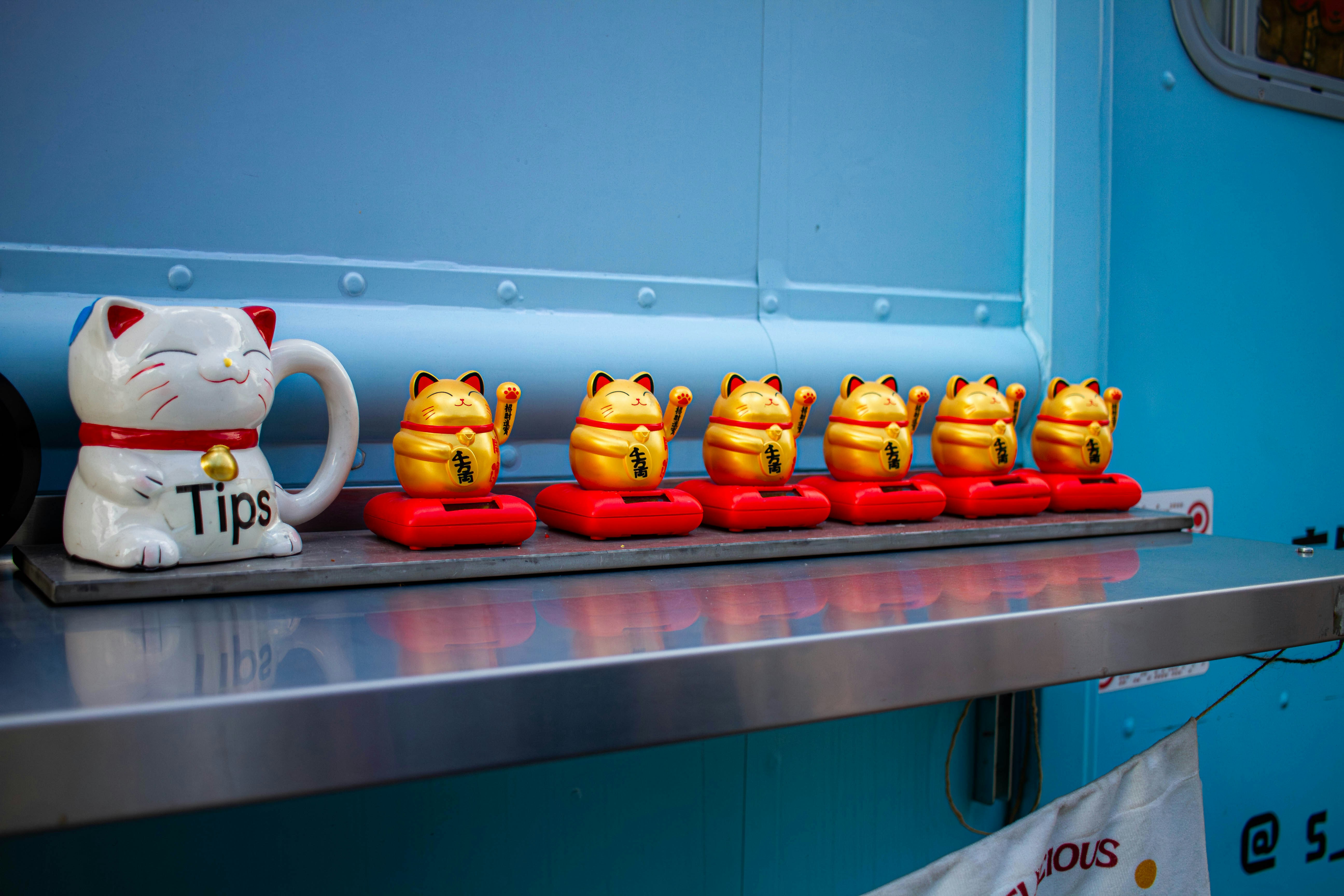 Row of Lucky Cat Tips: Acrylic smiles on a blue backdrop