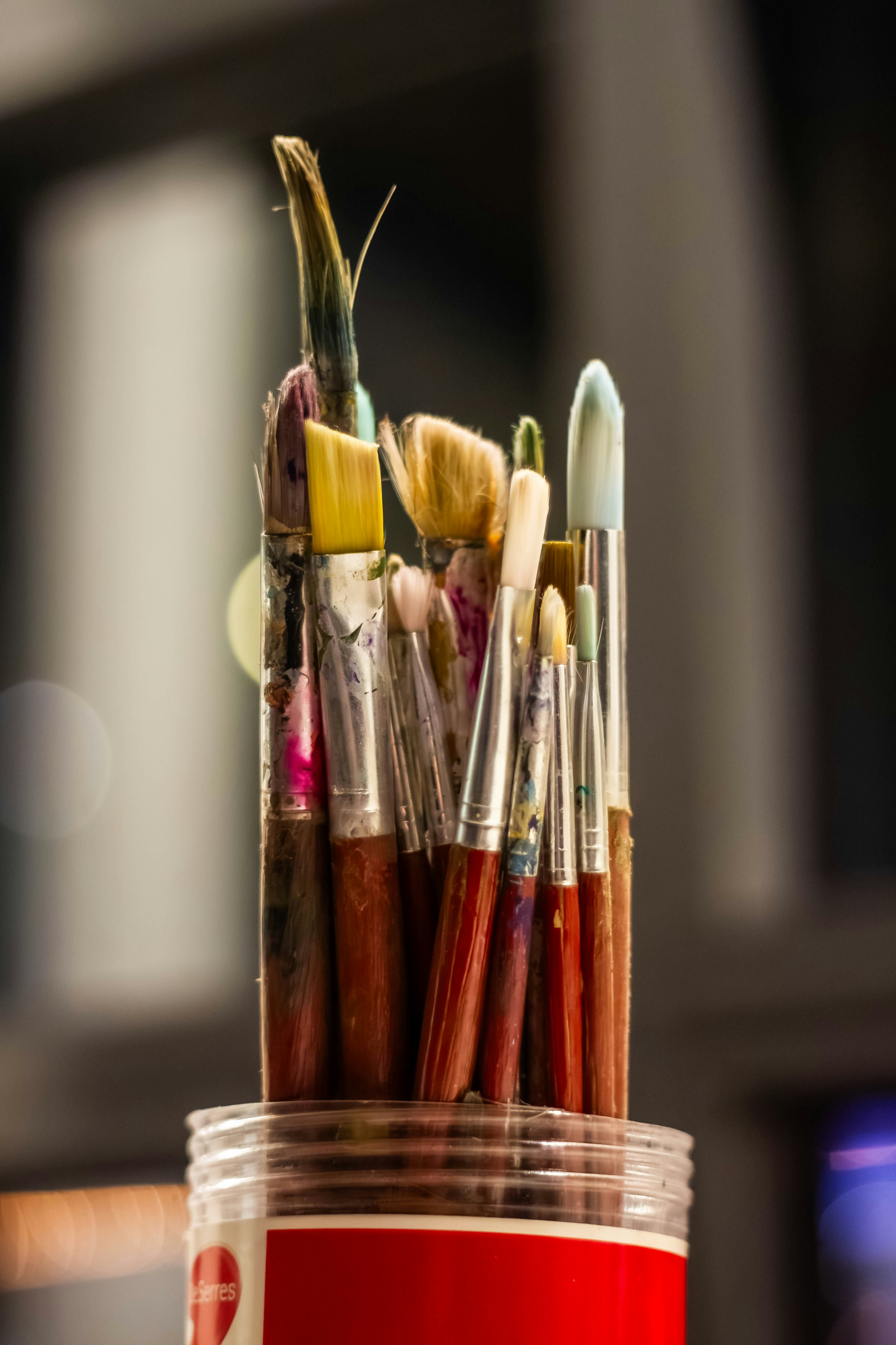 Bundle of Paintbrushes Standing Tall in a Red Jar