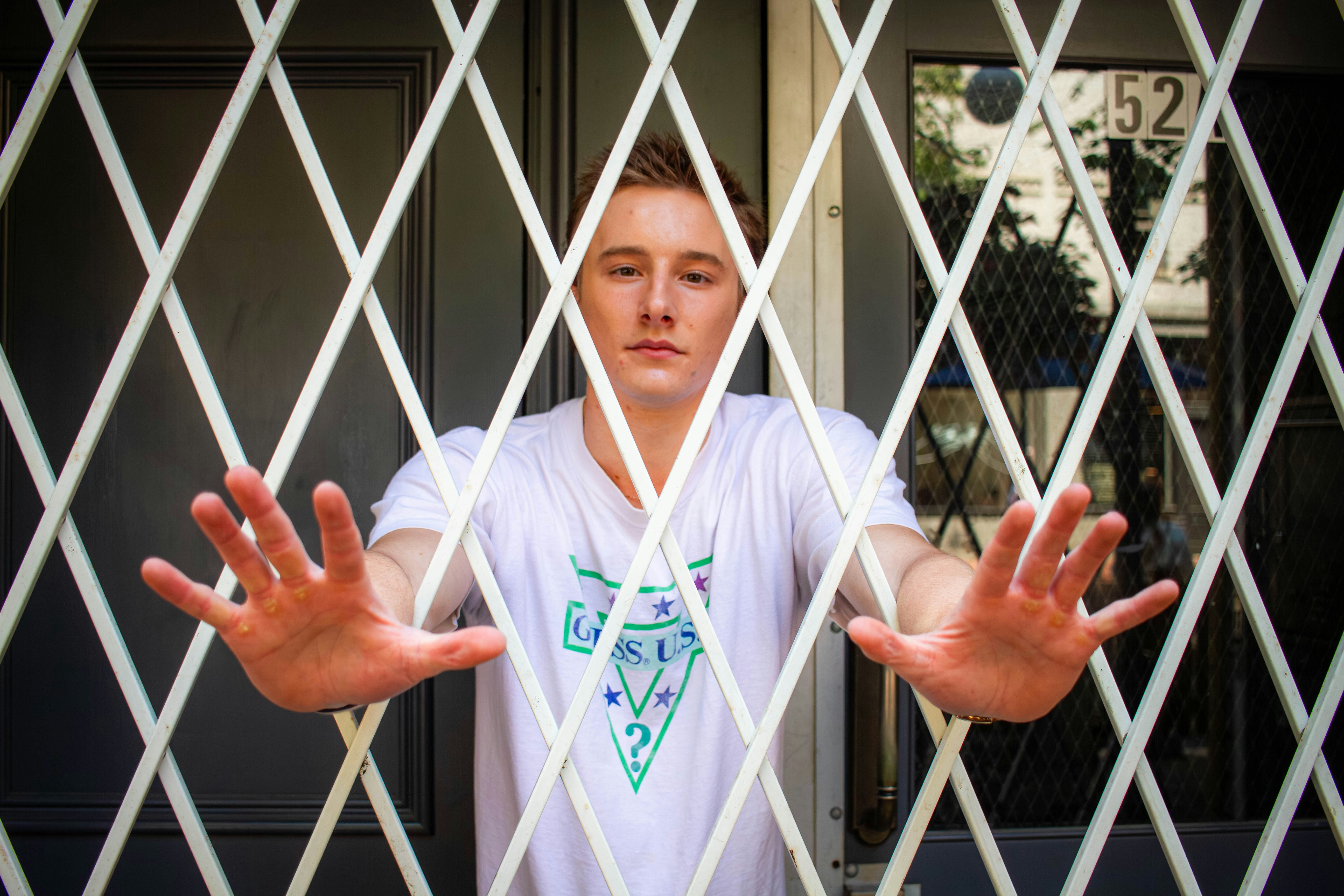 Hands on the Gate: A Portrait Through Barred Light