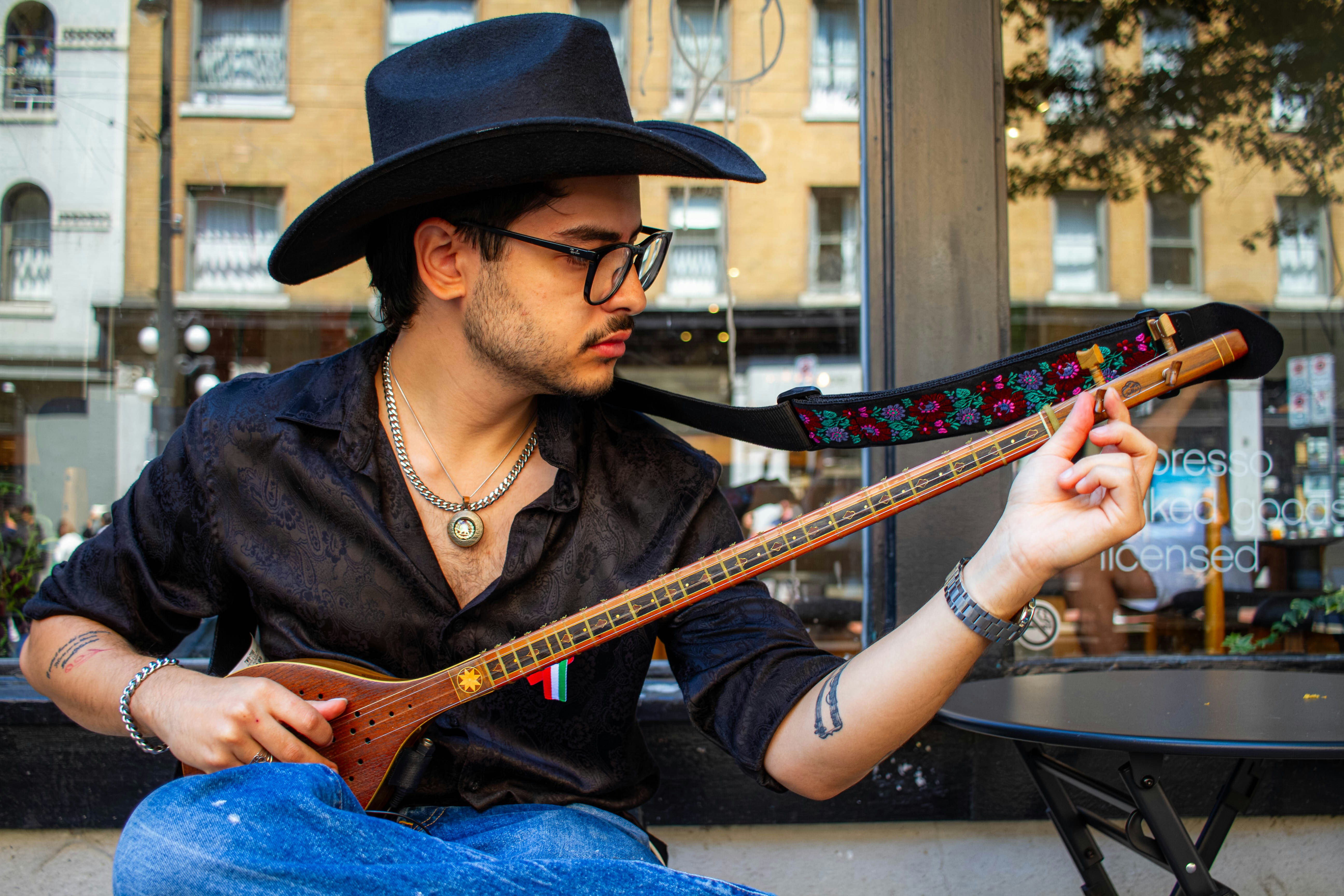 Sideways Serenade: A Street Musican in a Wide-Brimmed Hat Plays a Stringed Instrument