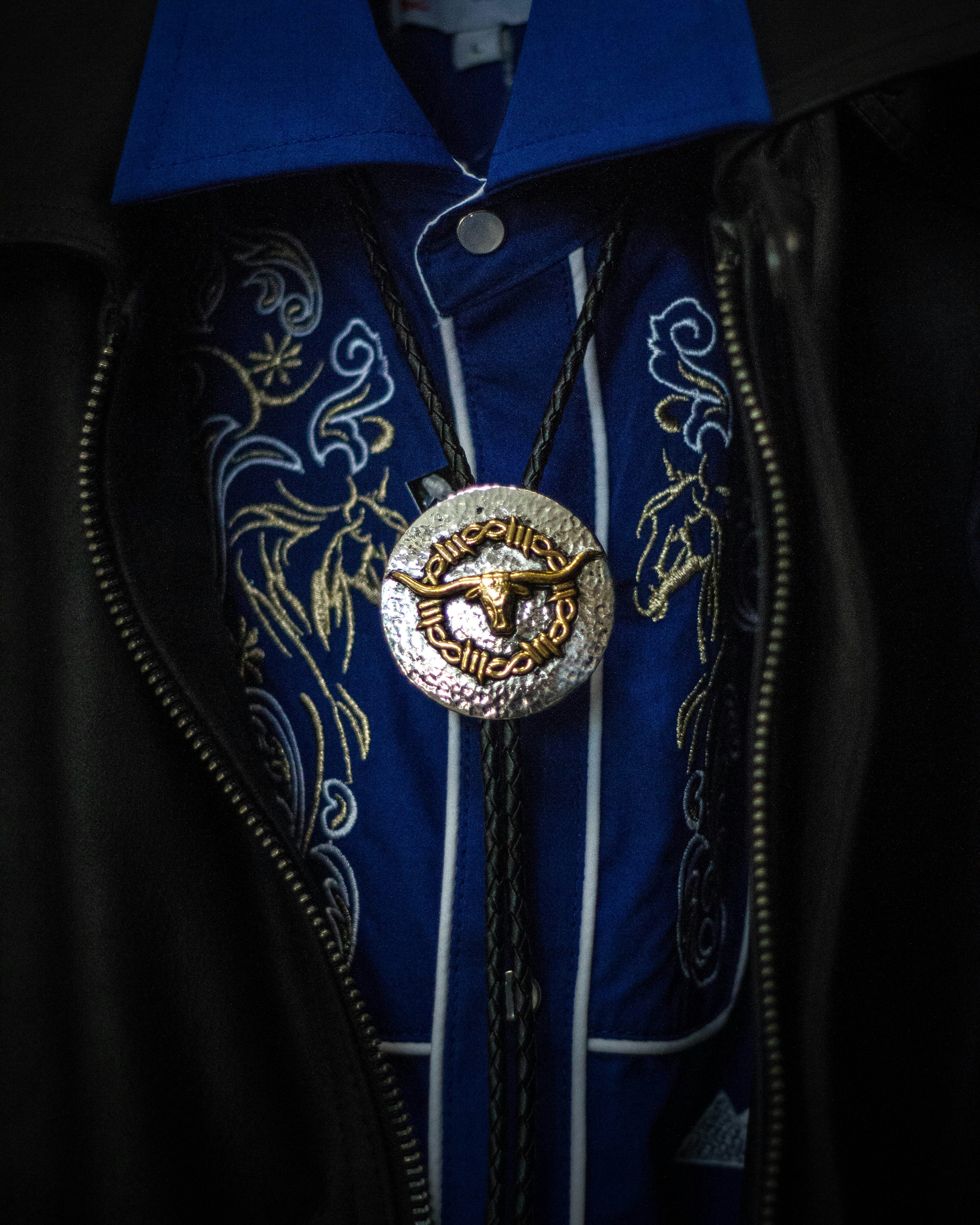 Emblem on Blue Vest: A Cowboy Icon Pendant Resting on Embroidered Shirt