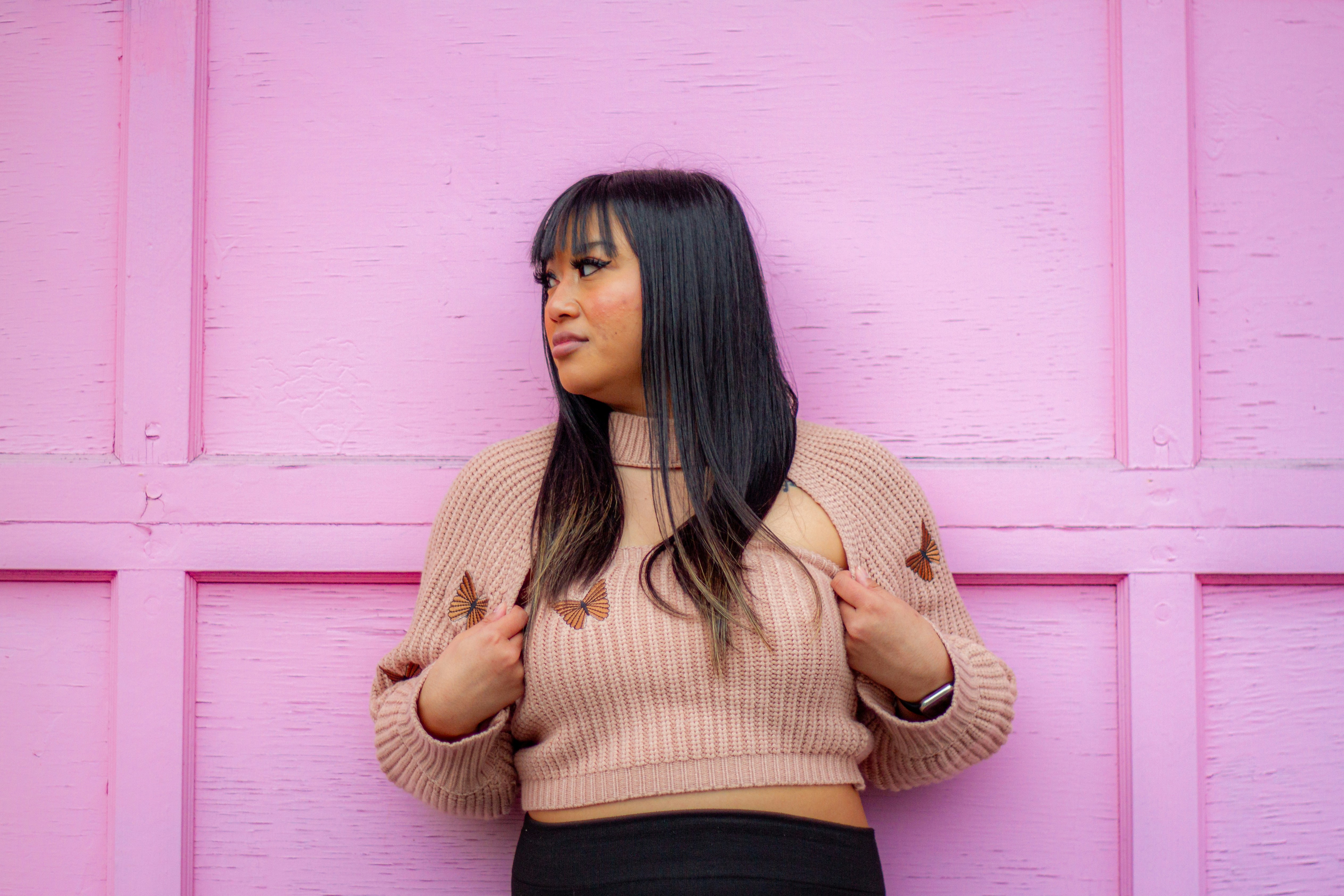 Pink Wall Portrait: A Shaded Smile Beneath Torn Knit