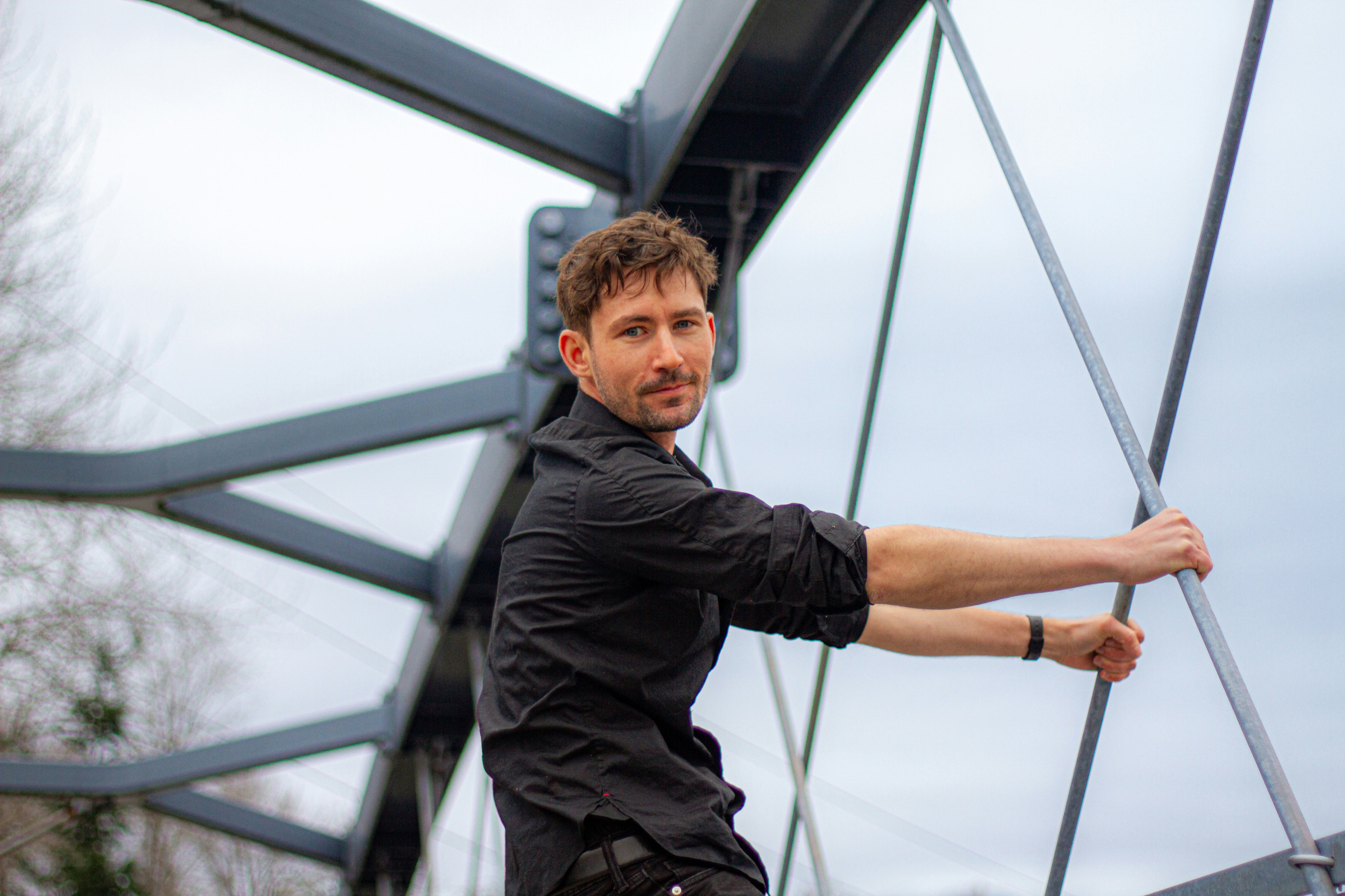 Climber on a steel bridge: the gaze and grip amid lattice shadows
