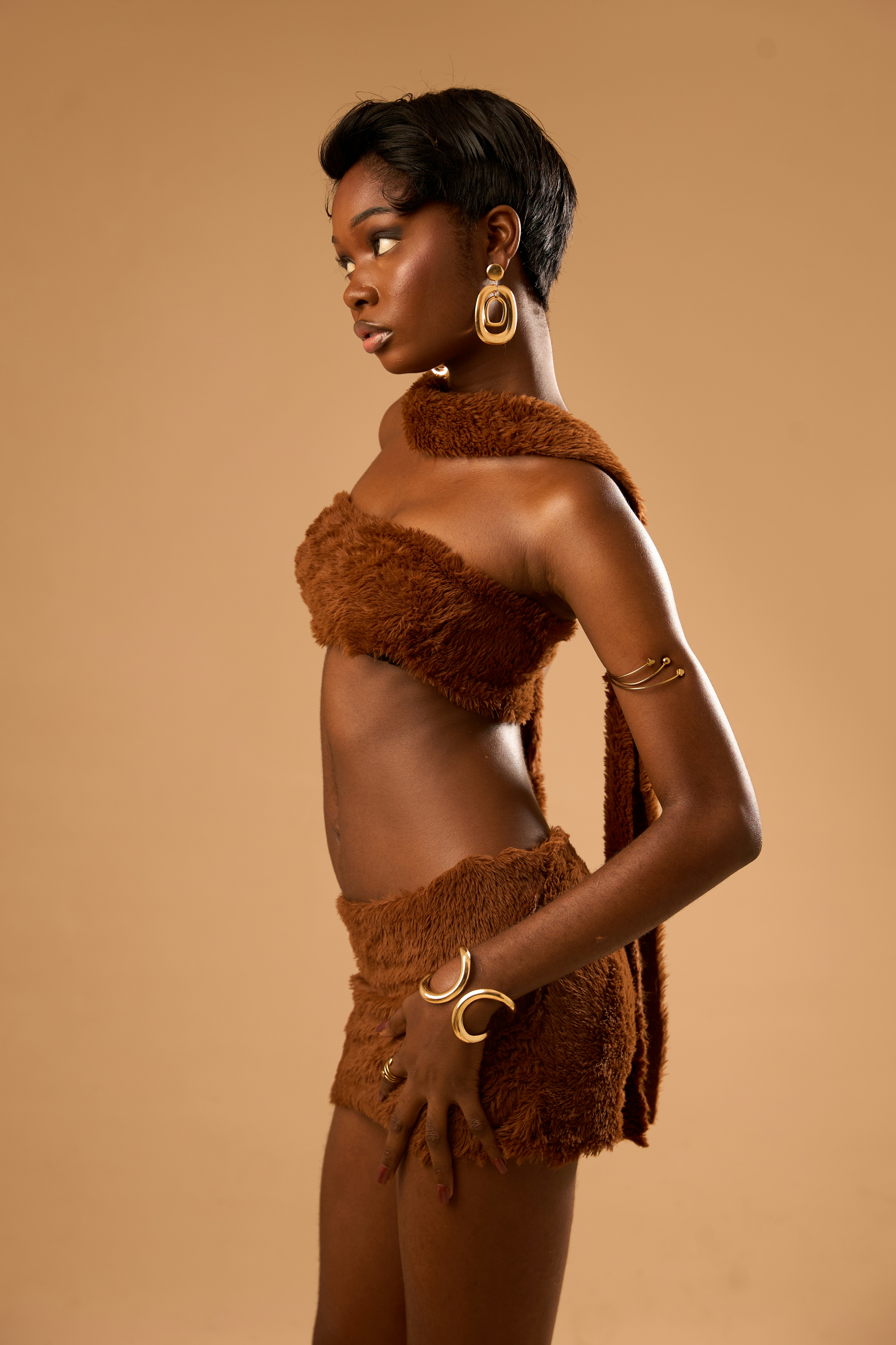 Young black woman in furry brown outfit with gold jewelry
