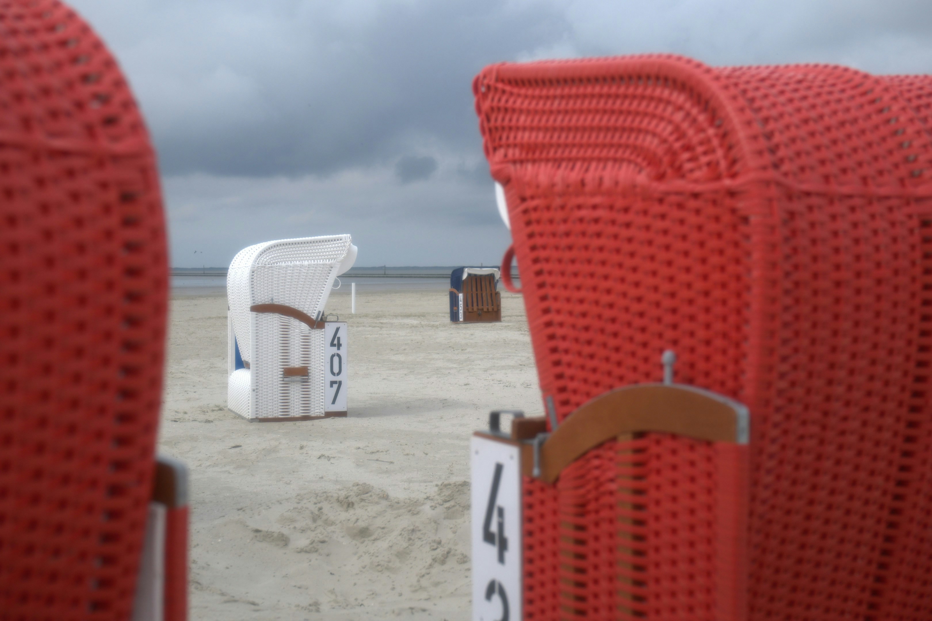 Midday Beach Stacks: Red Lounge Chairs Framing Quiet Dune
