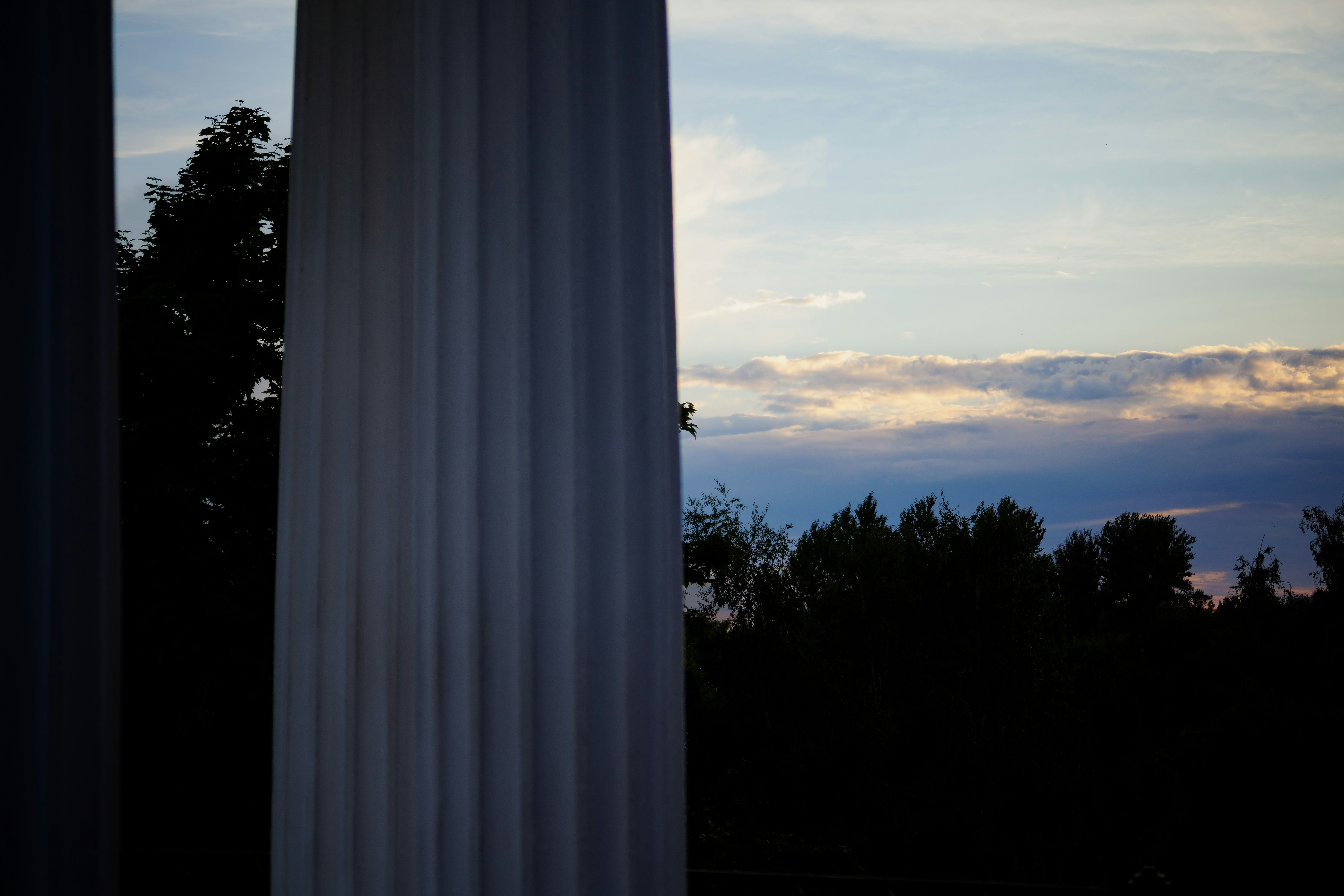 Curtain Between Dusk and Rooftop Silhouettes