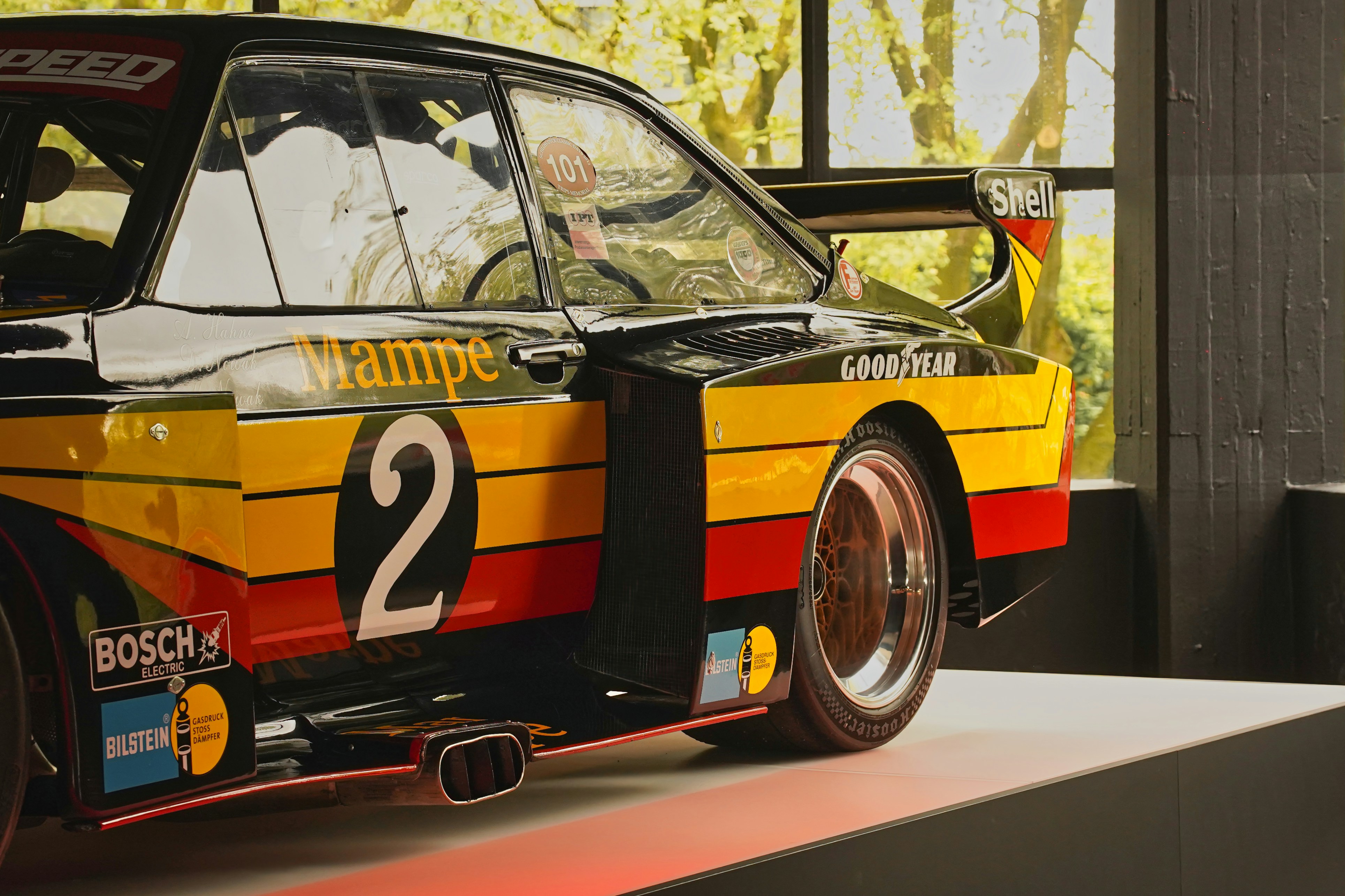Vintage race car on display: bold yellow-orange stripework and number 2